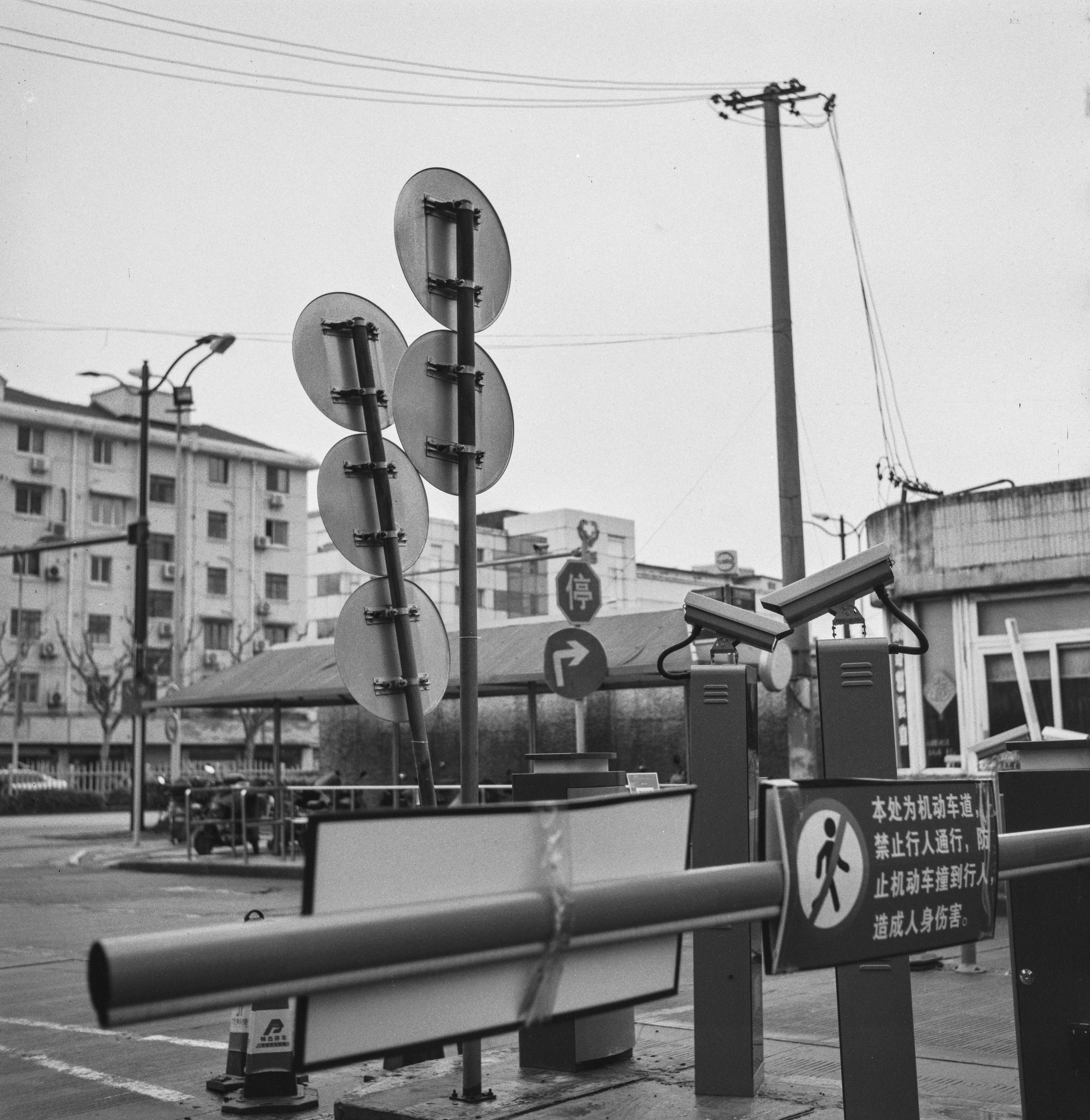 Threshold of Movement: Barrier Gate Framed by a Tower of Road Signs