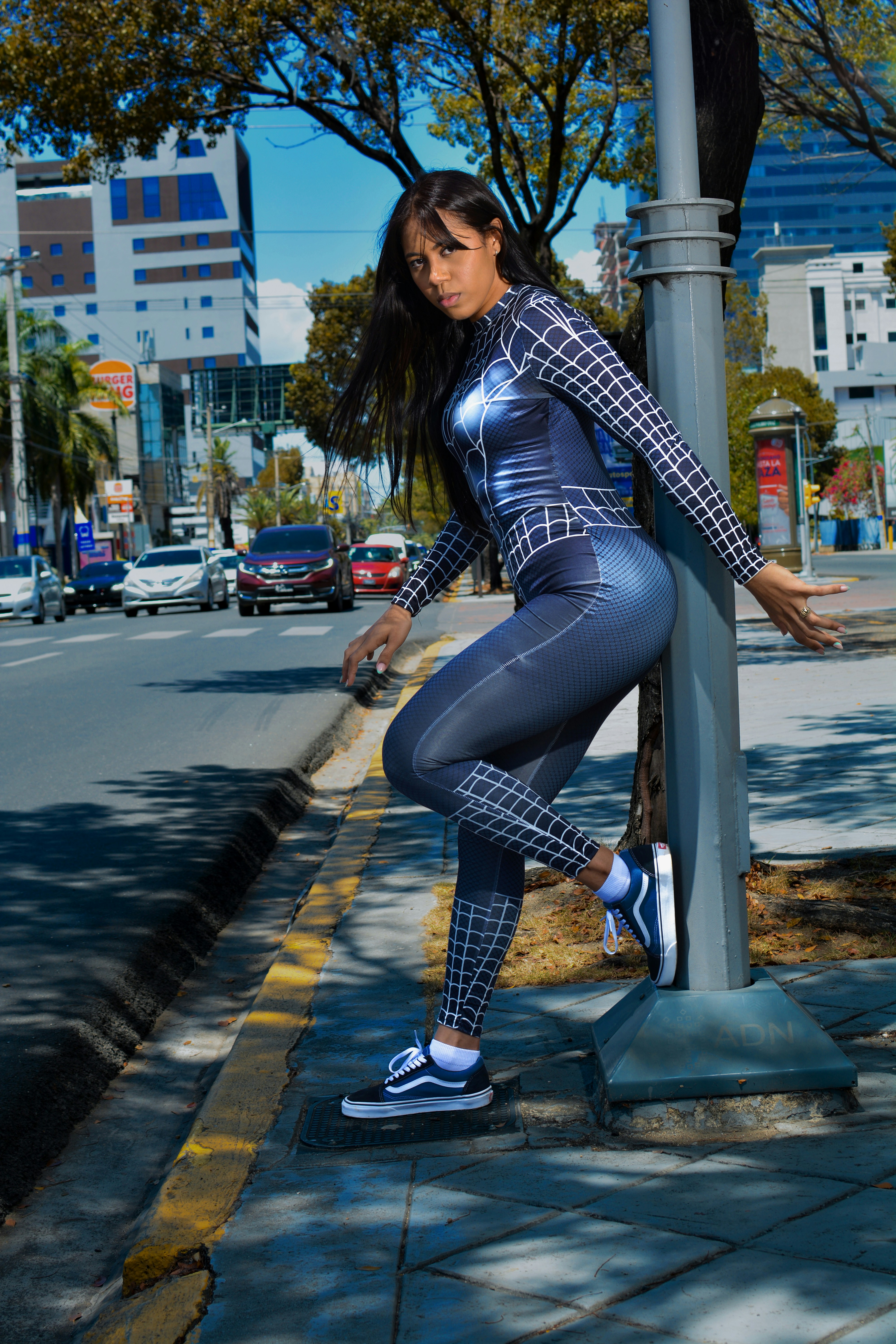 A woman leaning against a pole on a city street photo – Free Shoe Image ...