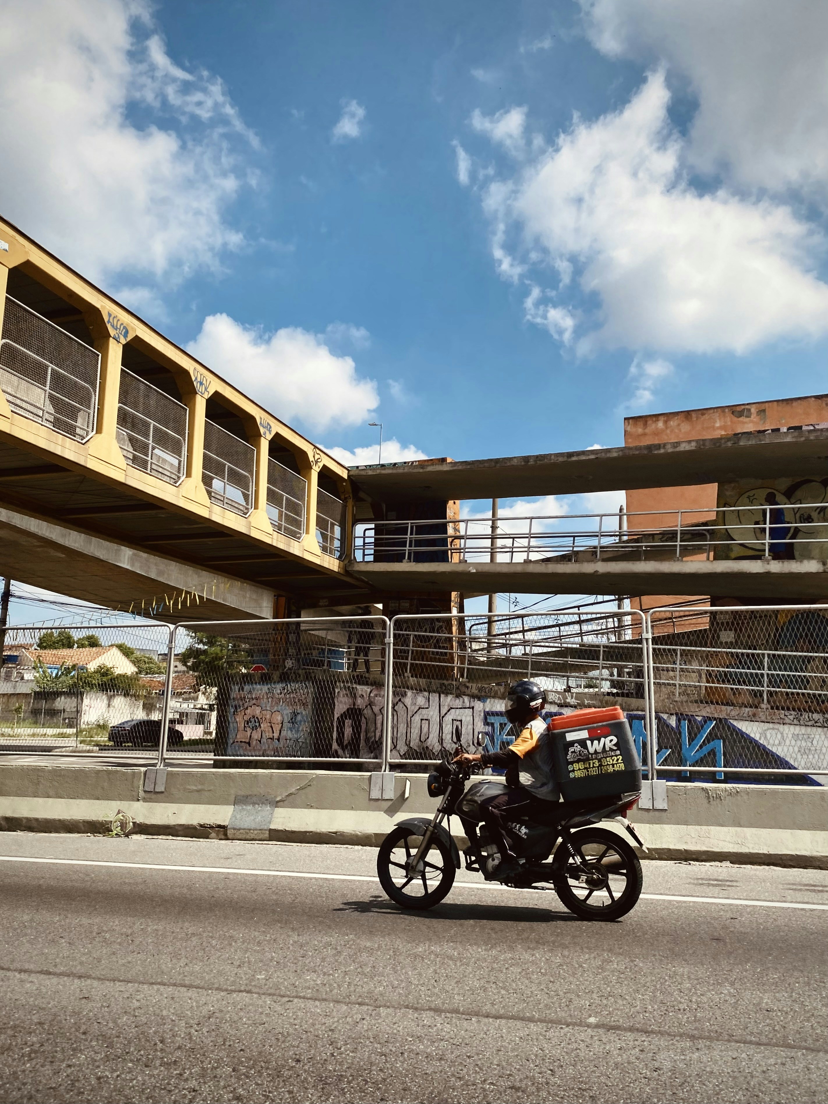 A man riding a motorcycle down a street under a bridge photo – Free Rio ...