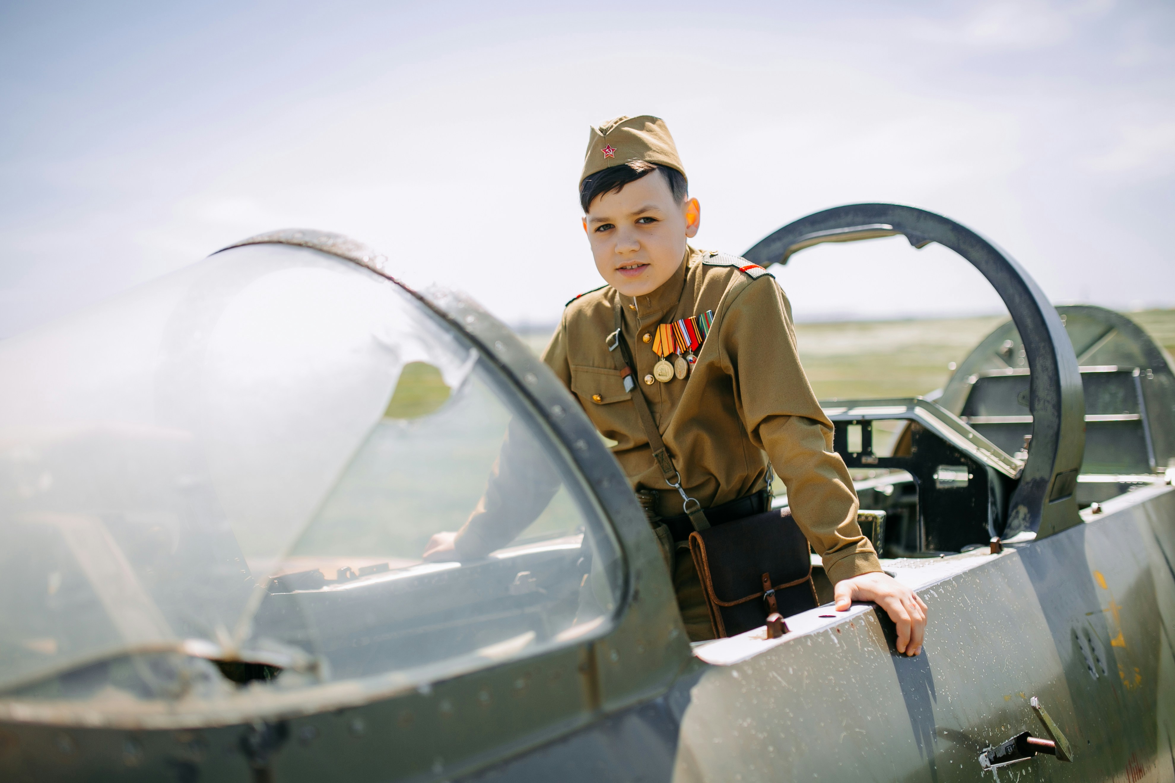 A boy in a military uniform leaning out of an airplane window photo ...