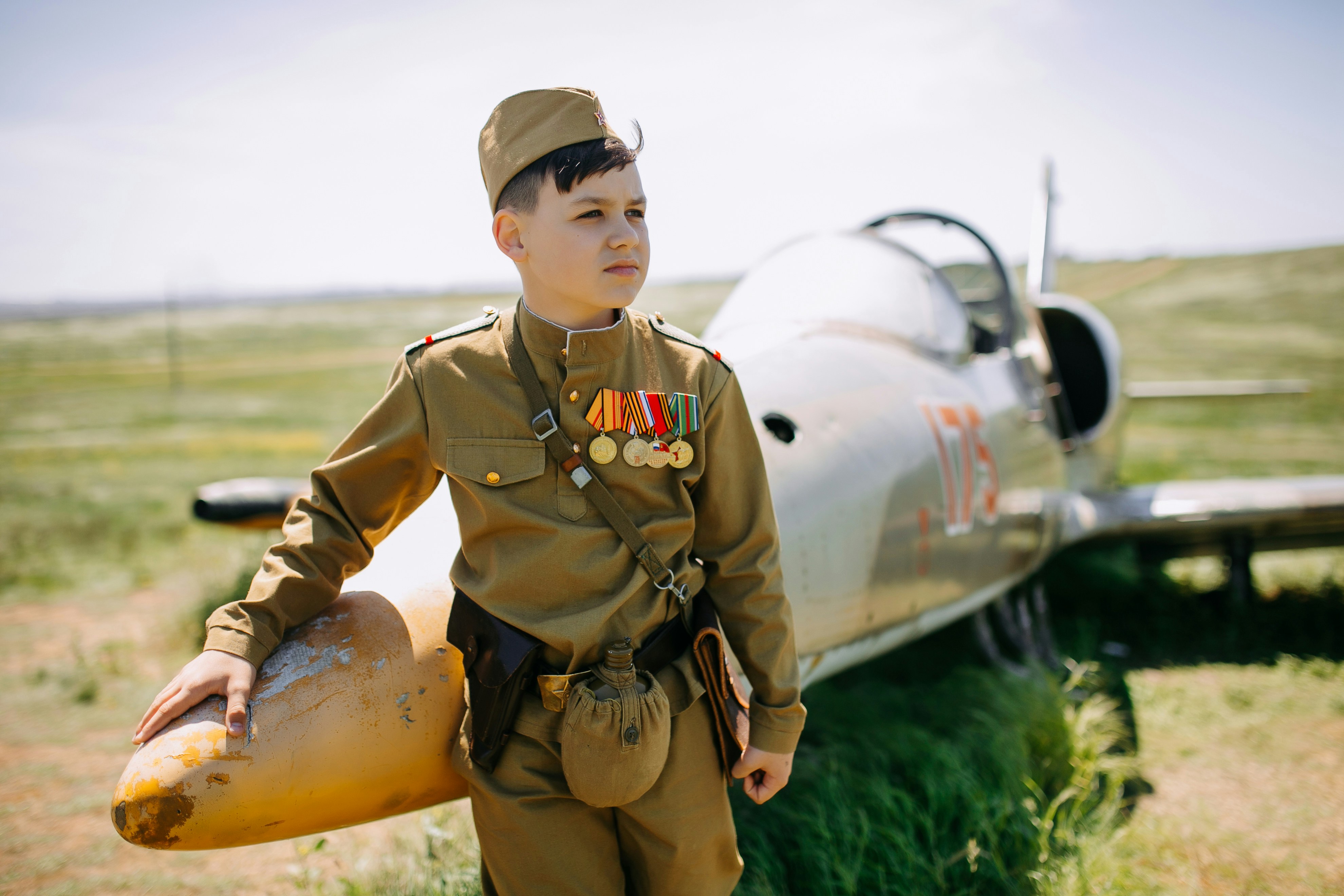 A young boy in uniform standing next to an airplane photo – Free Boy ...