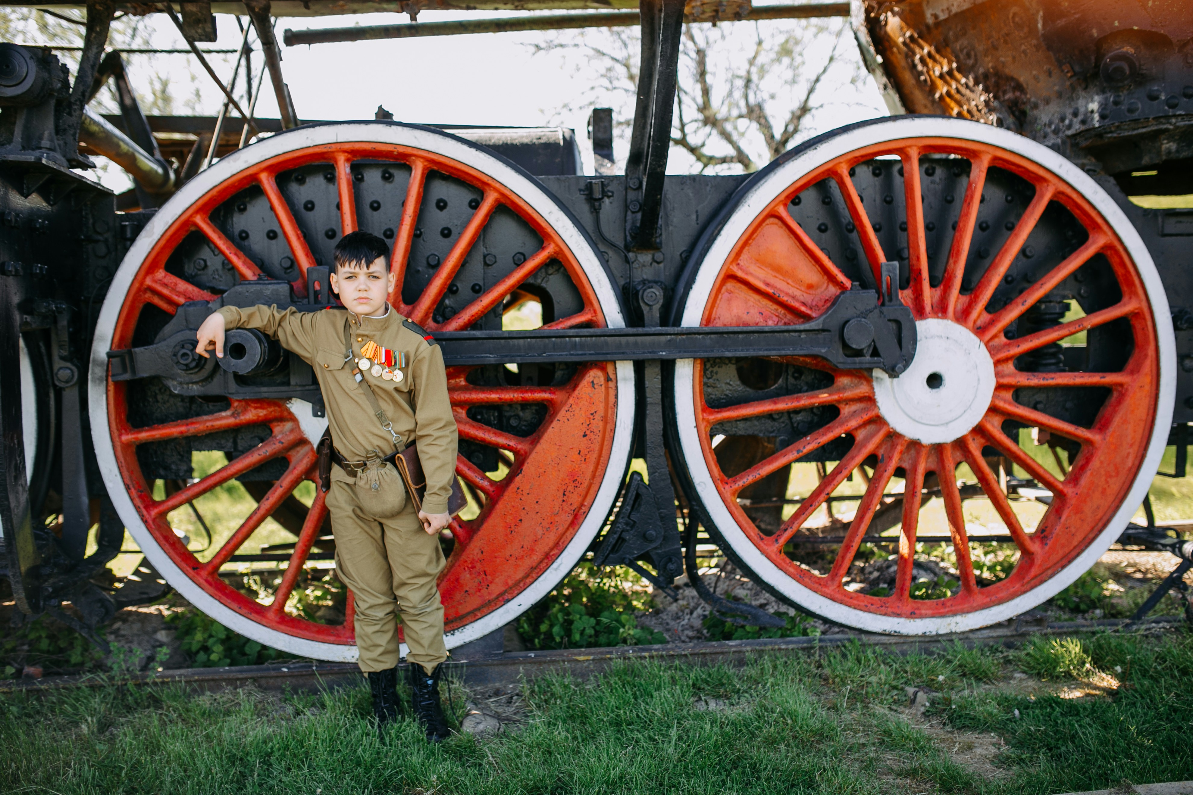 A boy in uniform standing next to a train wheel photo – Free Portrait ...
