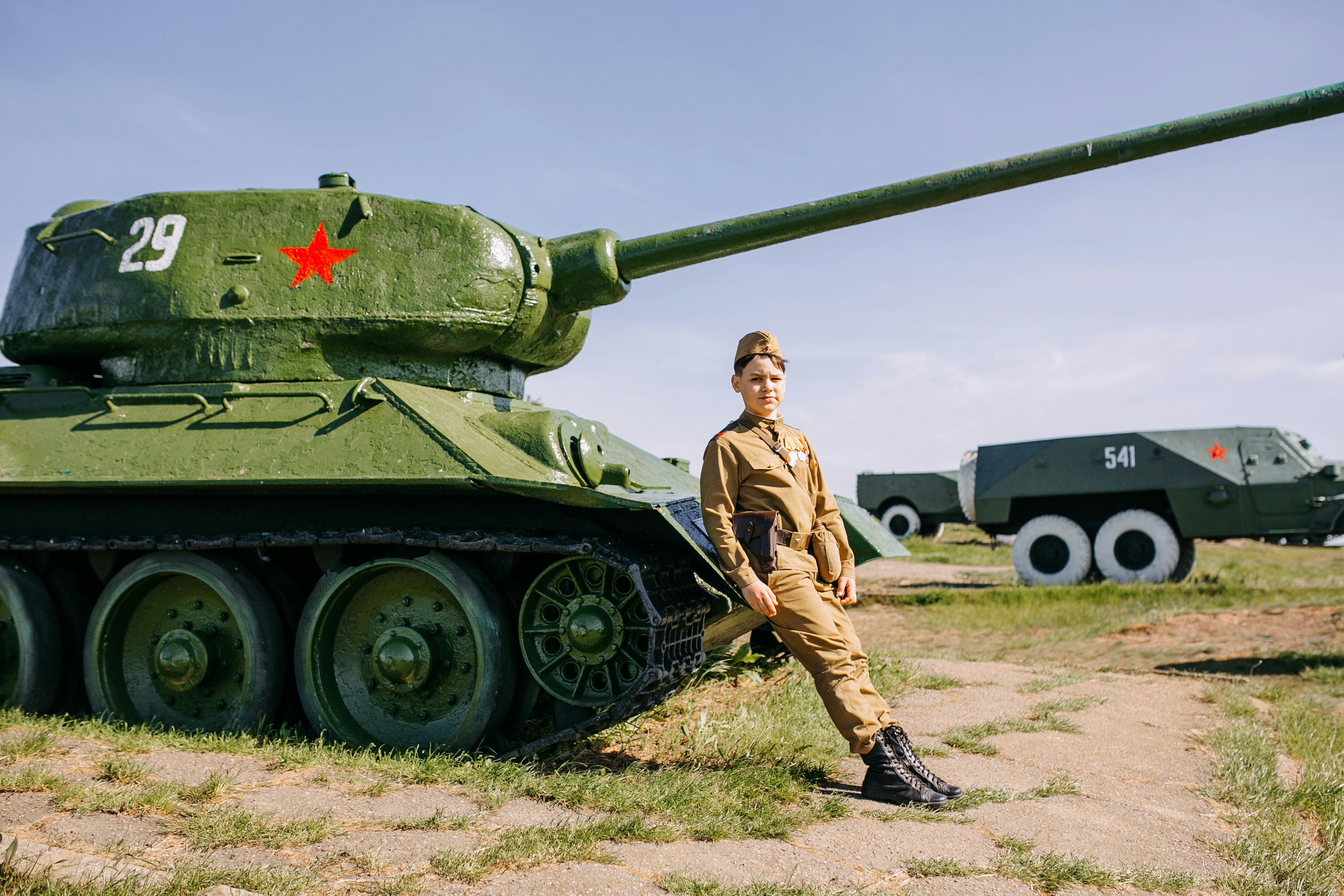 A man standing next to a tank in a field photo – Free Boy Image on Unsplash