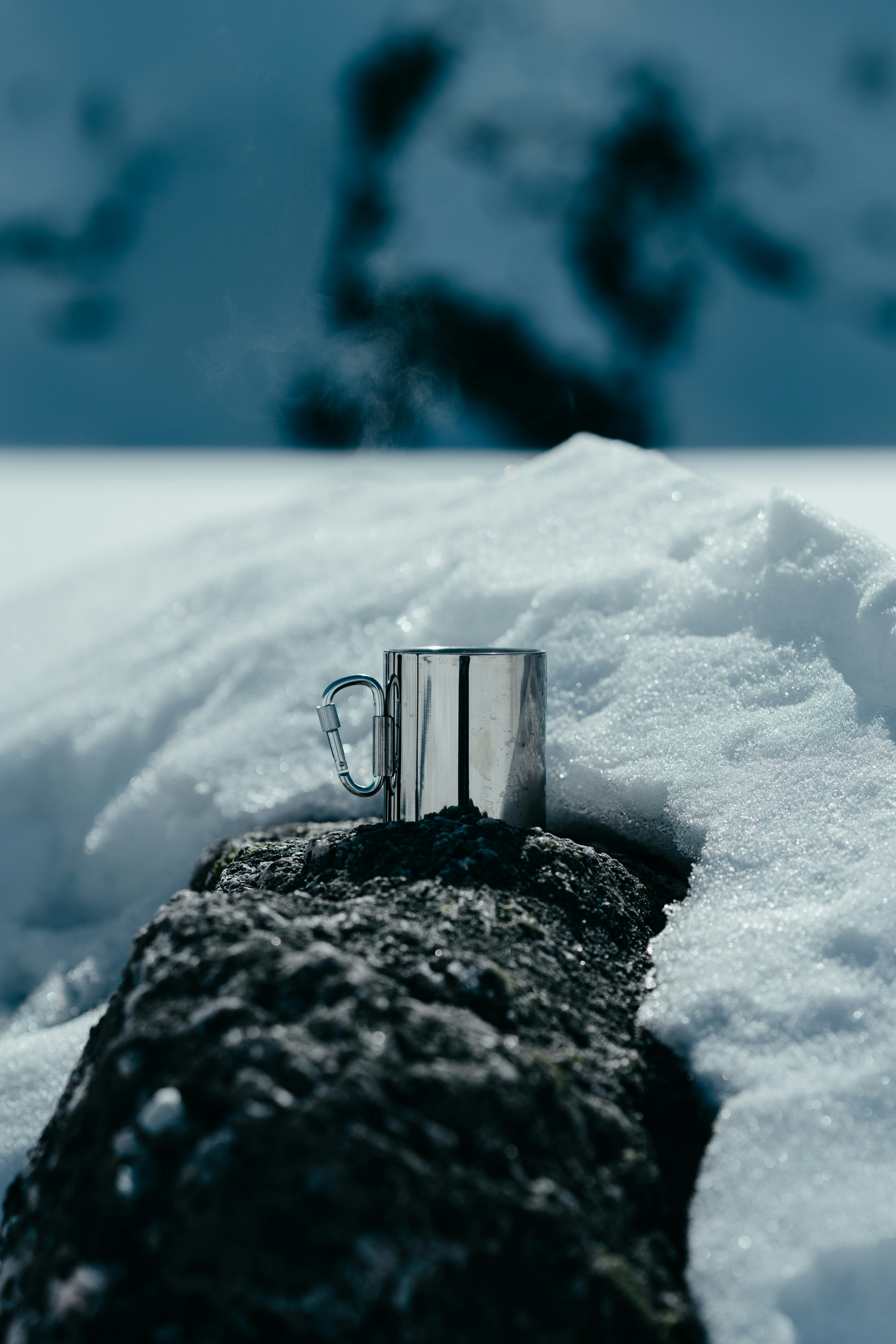 Shimmering Camp Mug on a Snow-Capped Log at Blue Hour