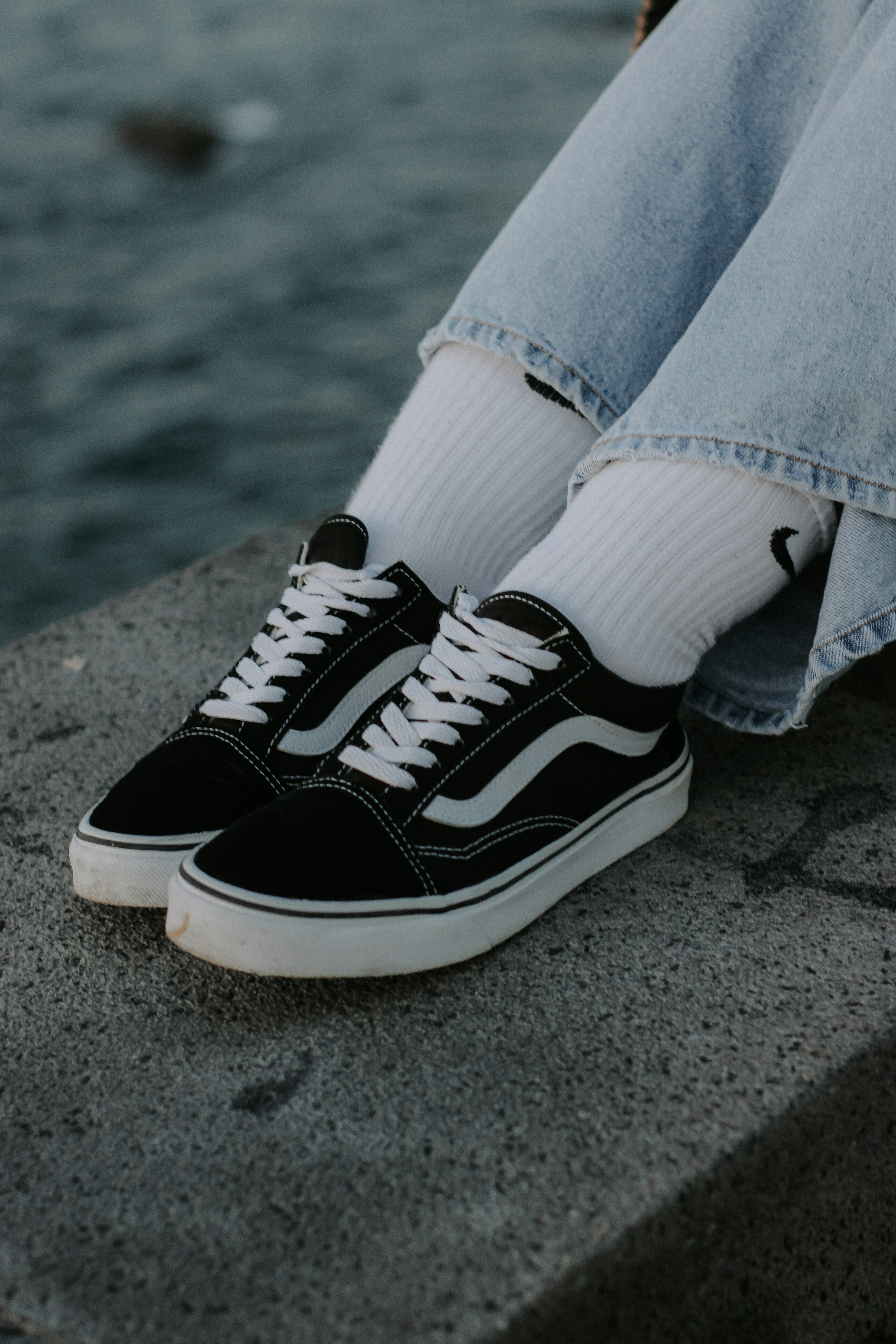 A person wearing black and white shoes sitting on a ledge photo – Free ...