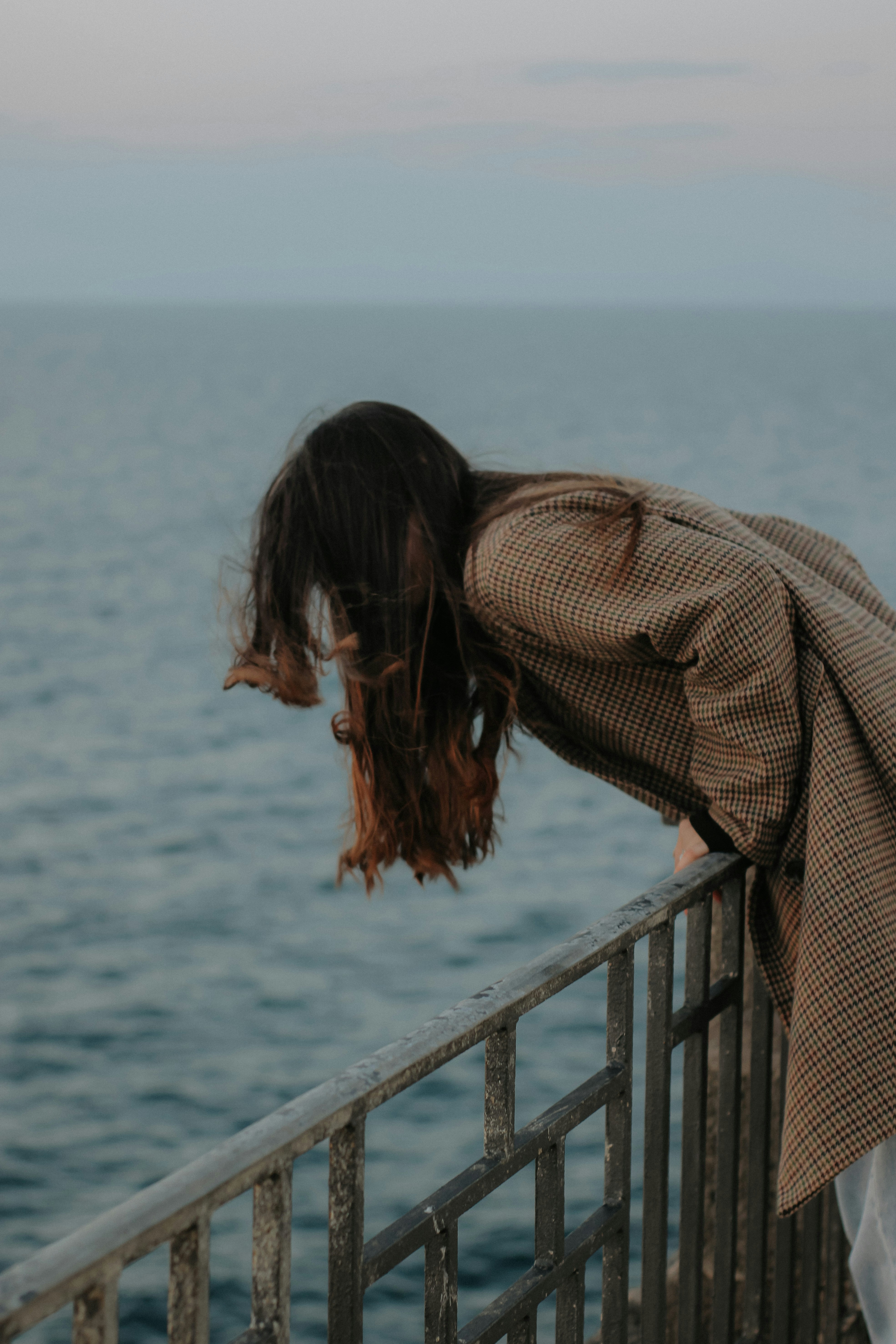 A woman leaning over a railing near the ocean photo – Free Portrait ...