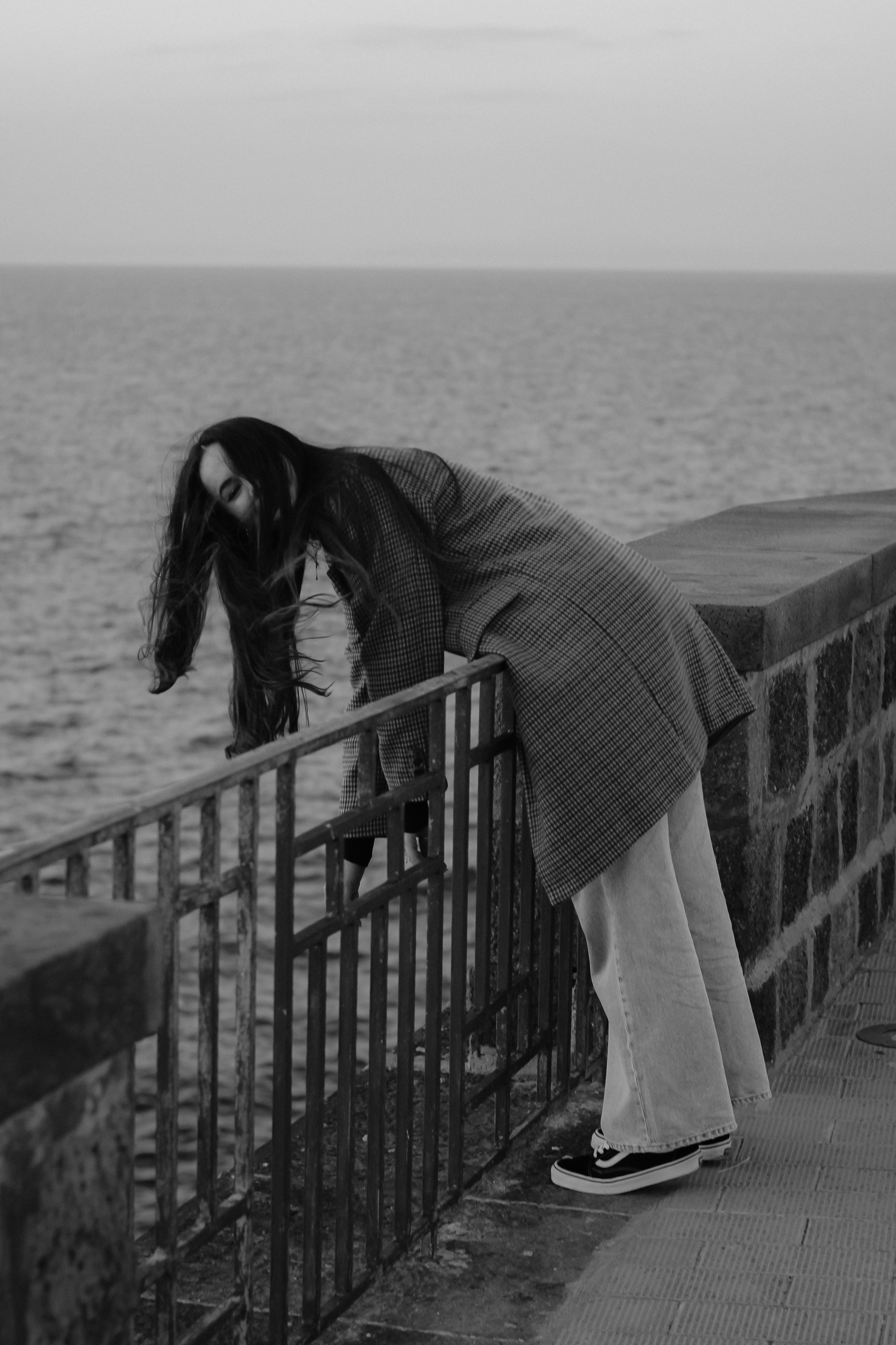 A woman leaning over a railing near the ocean photo – Free Ischia Image ...