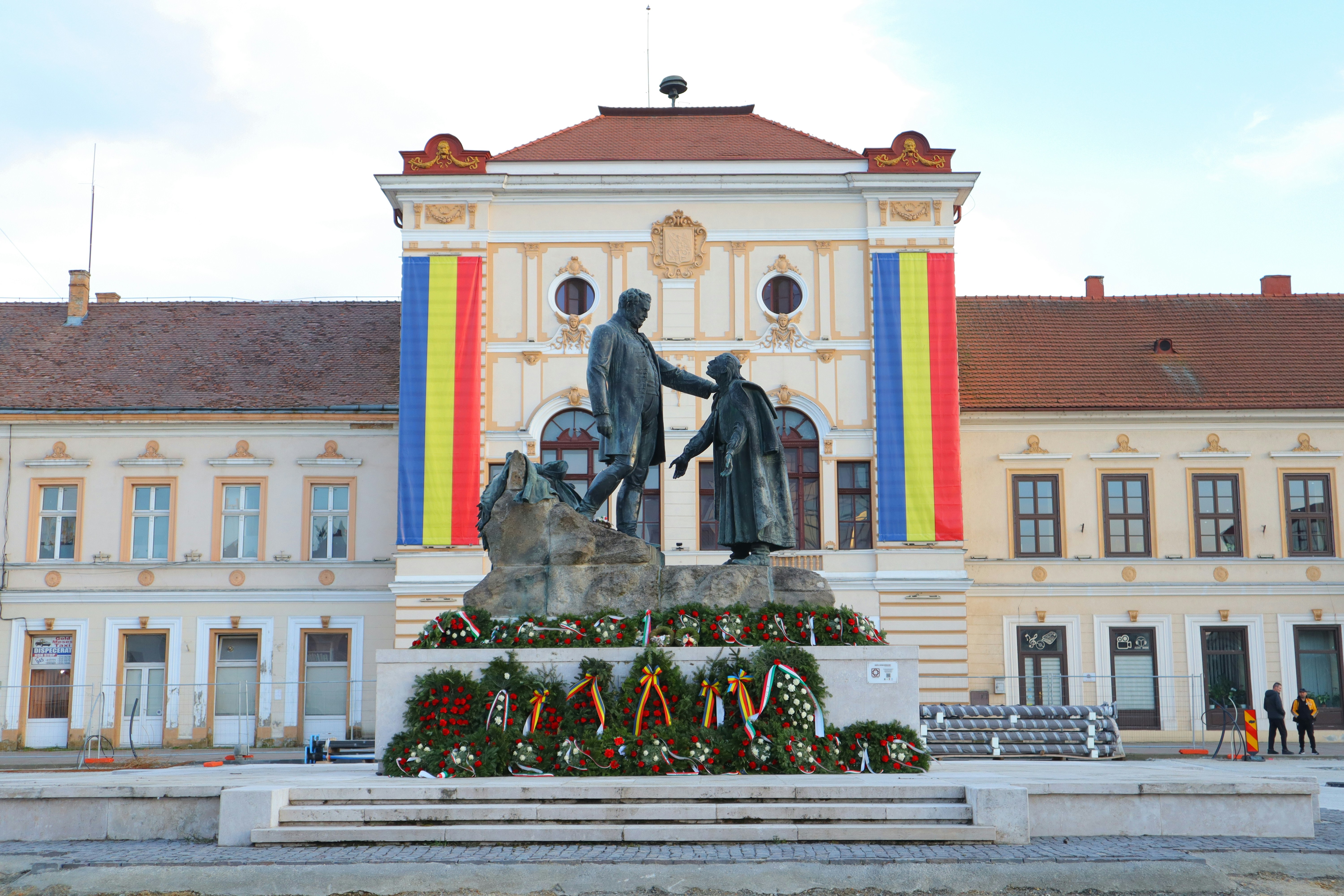 The Civic Gesture: Two Bronze Figures Before a Flags-Adorned City Facade