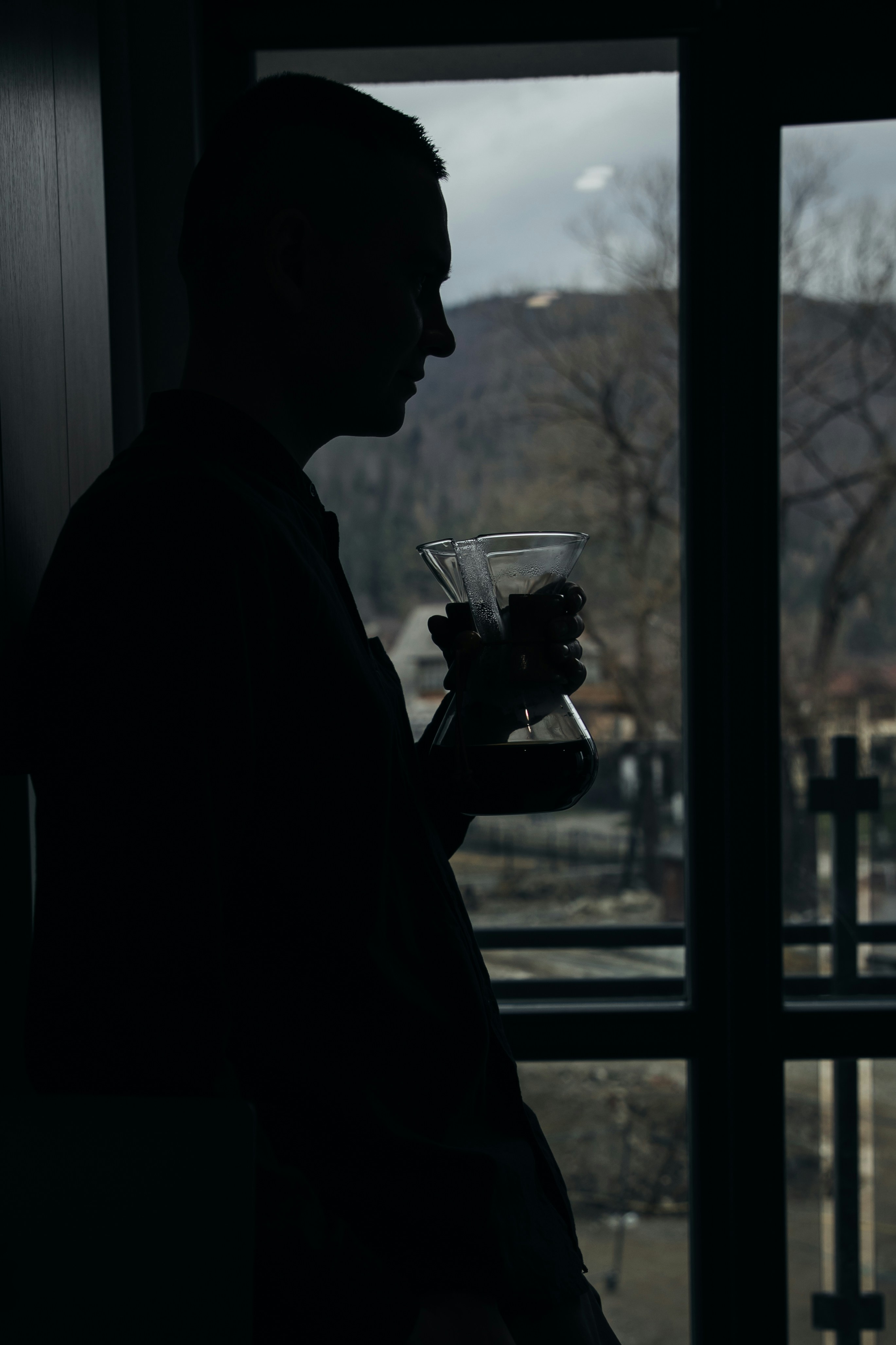 a man standing in front of a window holding a wine glass