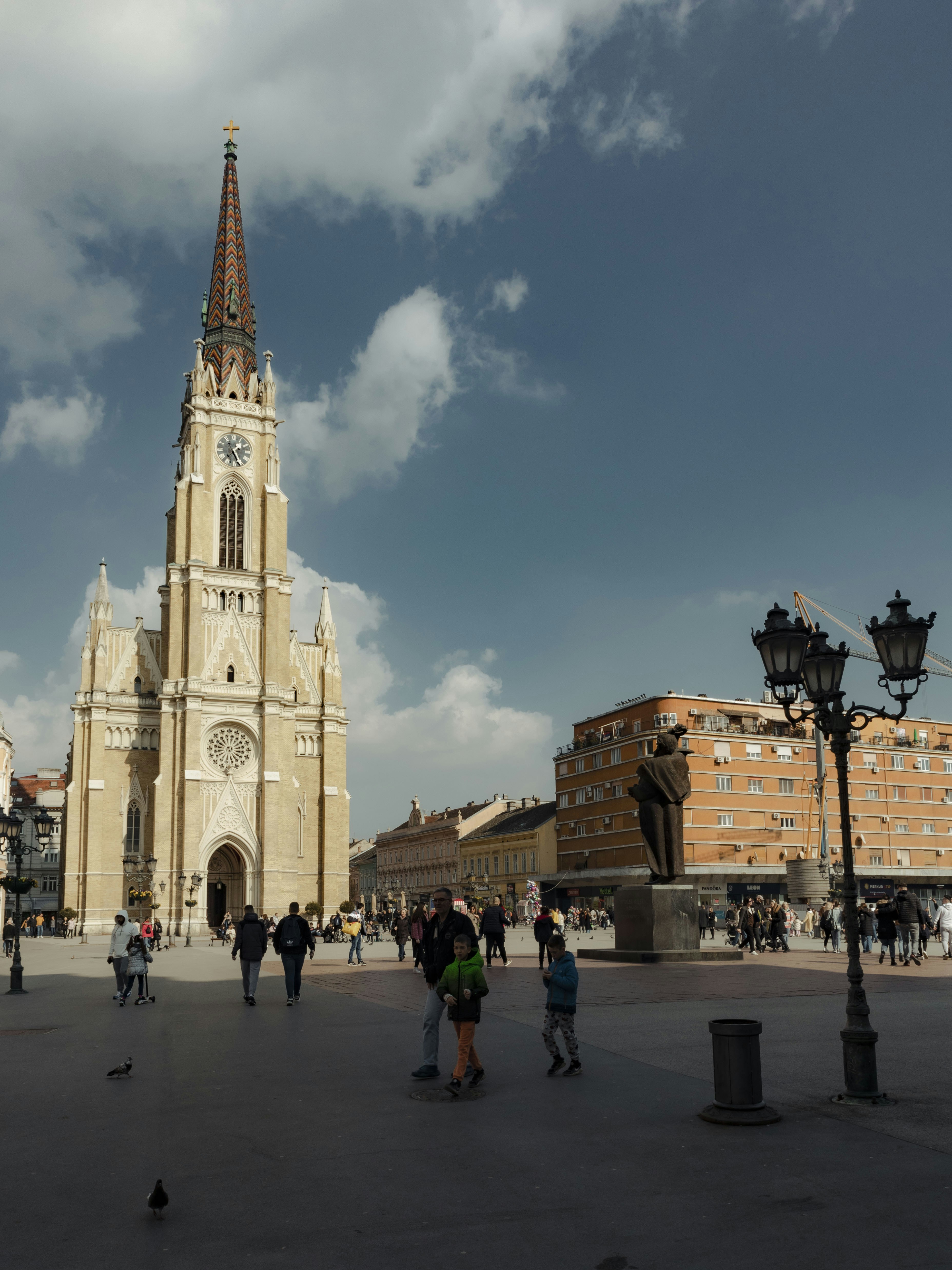 Historic church standing majestically in a bustling square filled with people and lively activity. The scene captures the essence of urban life and architectural beauty.