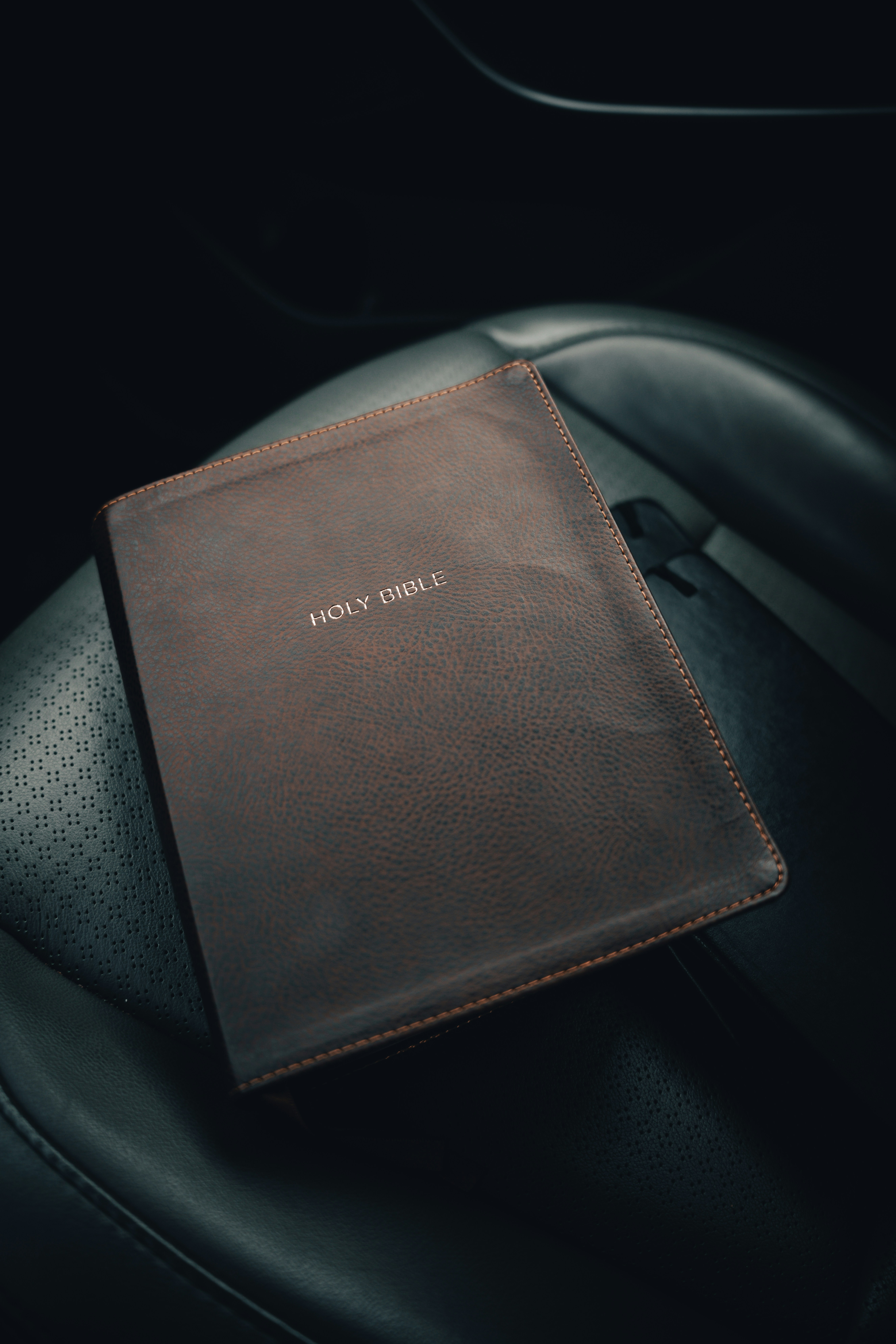 Leather-Bound Holy Bible Lying Diagonally Across a Car Seat