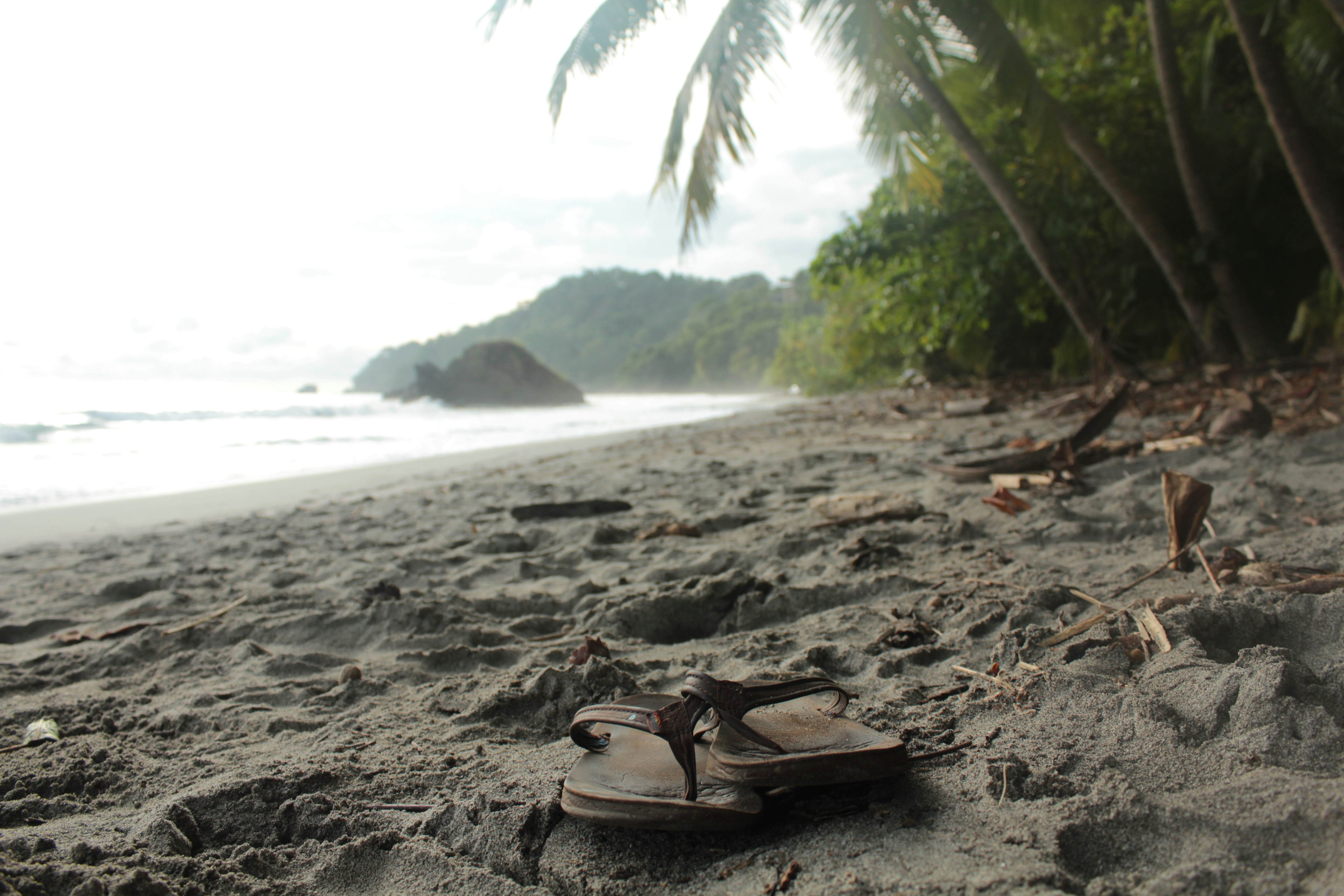 A pair of sandals sitting on top of a sandy beach photo – Free Outward ...