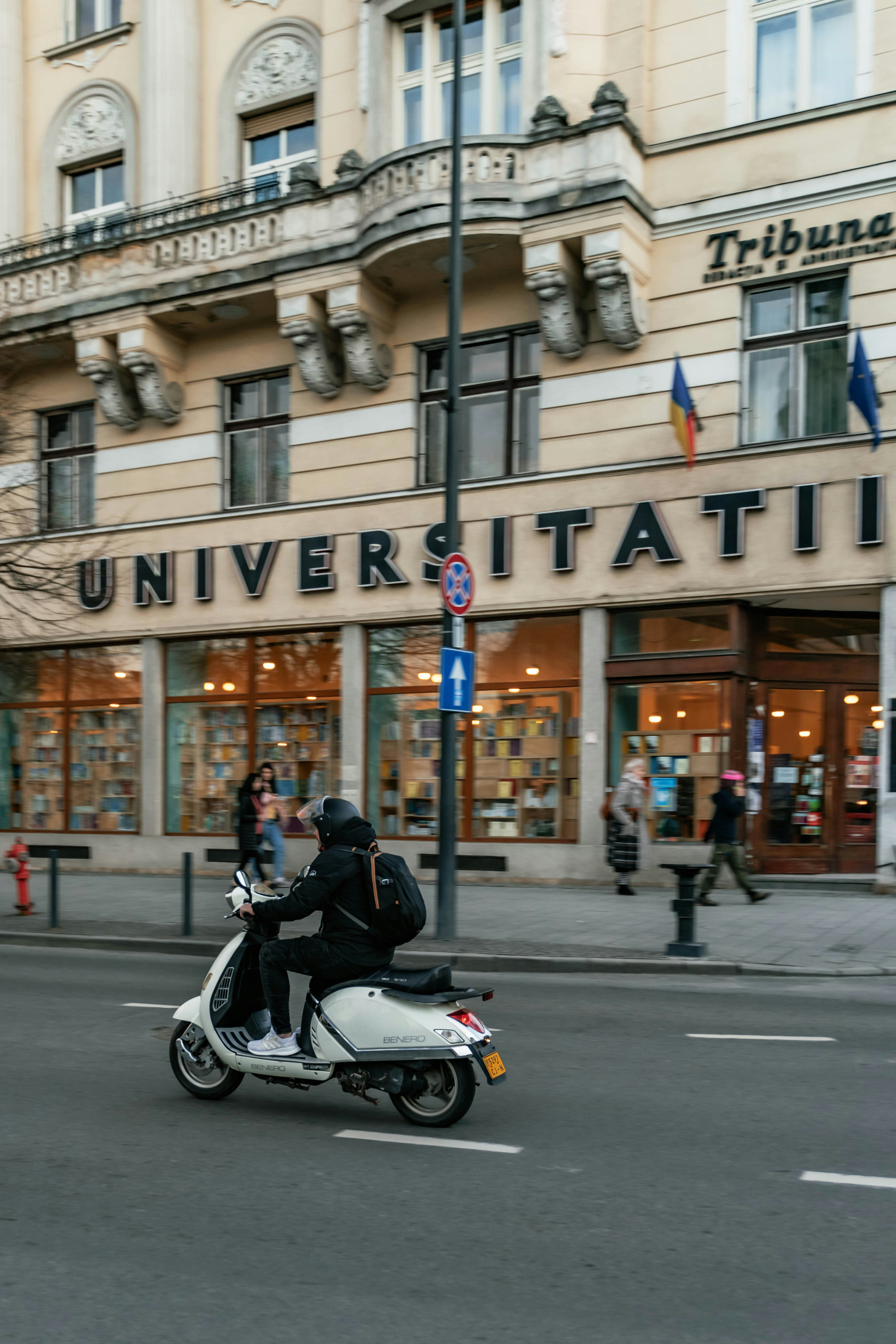 Scooter Glide Before a Grand European University Facade