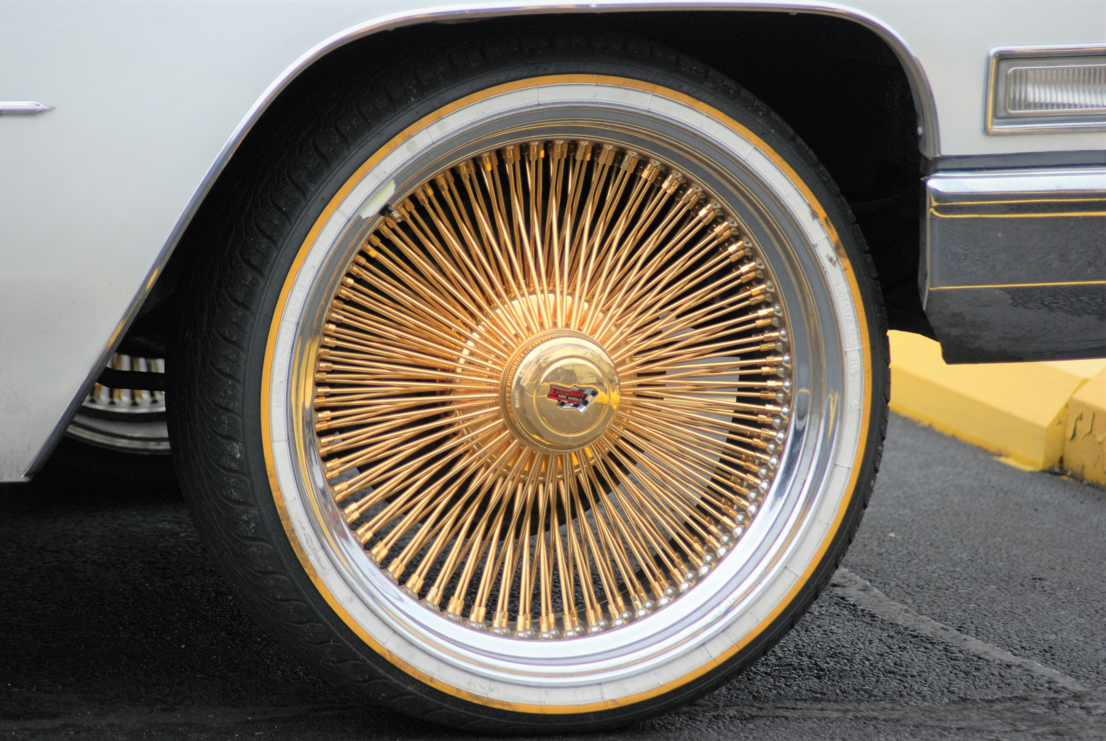 Close-up of an intricately designed gold-spoked wheel on a classic car, showcasing craftsmanship and style.