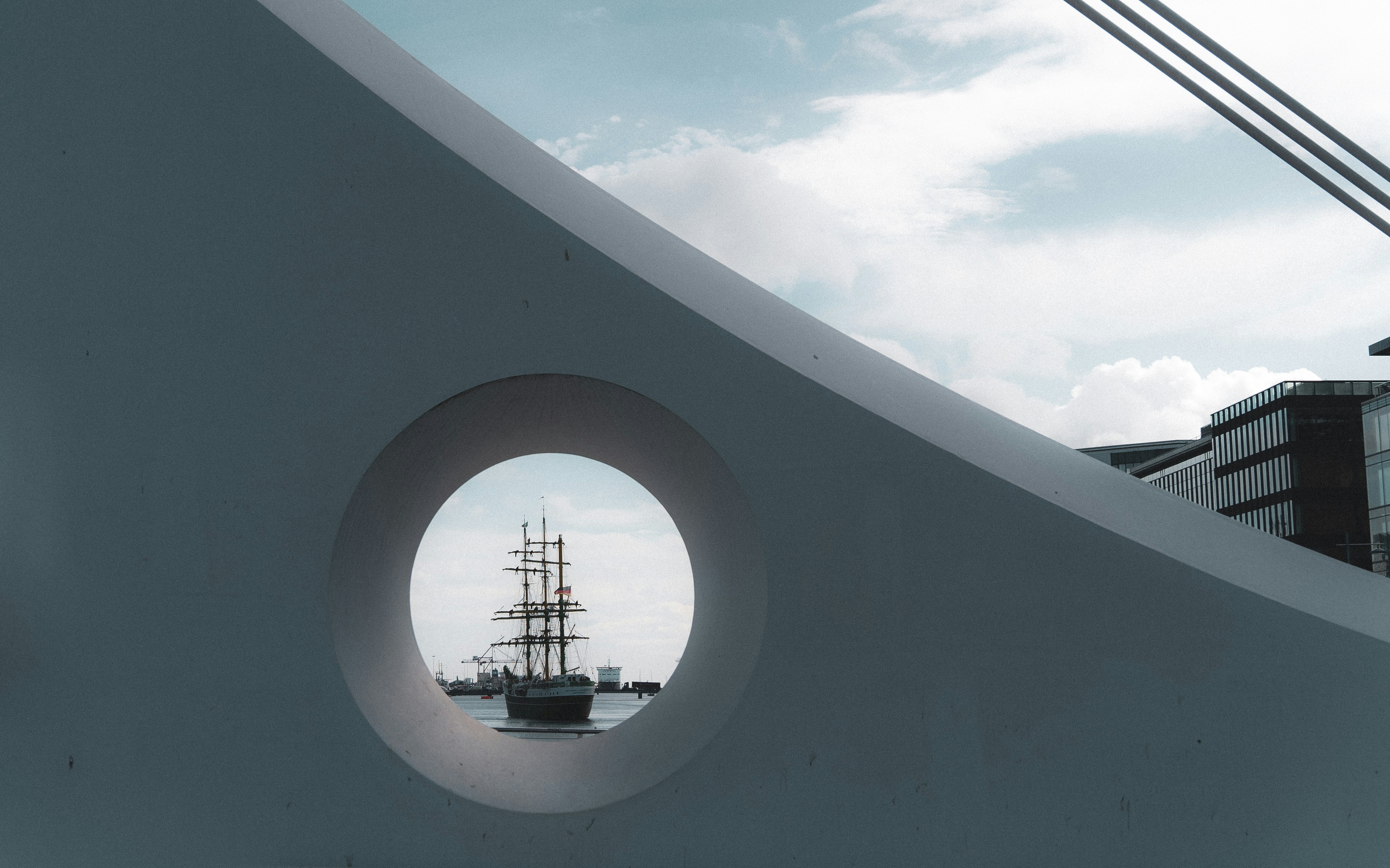 Through the Circular Window: A Sailboat Framed by Architecture