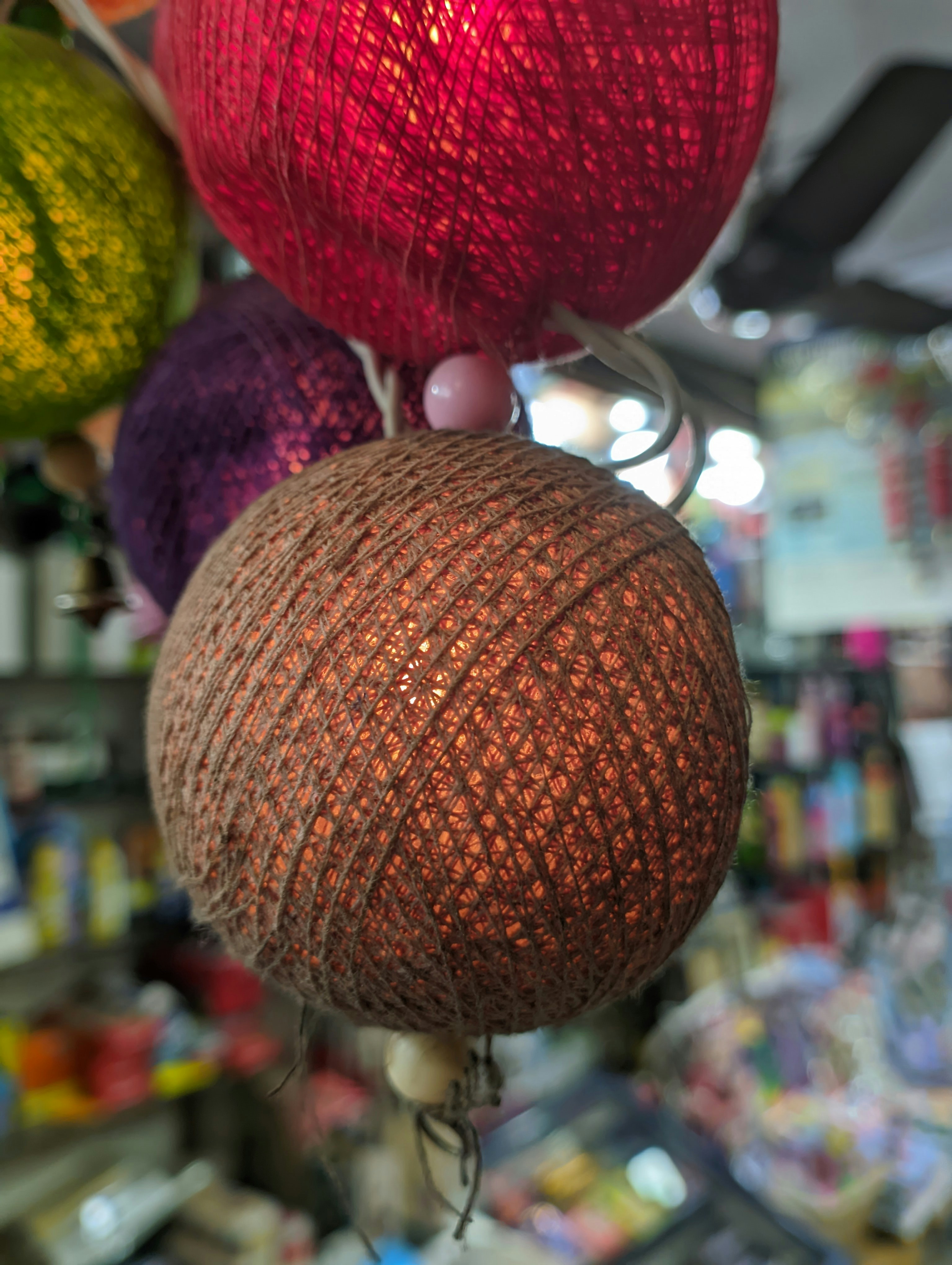 a bunch of balls of yarn hanging from a ceiling