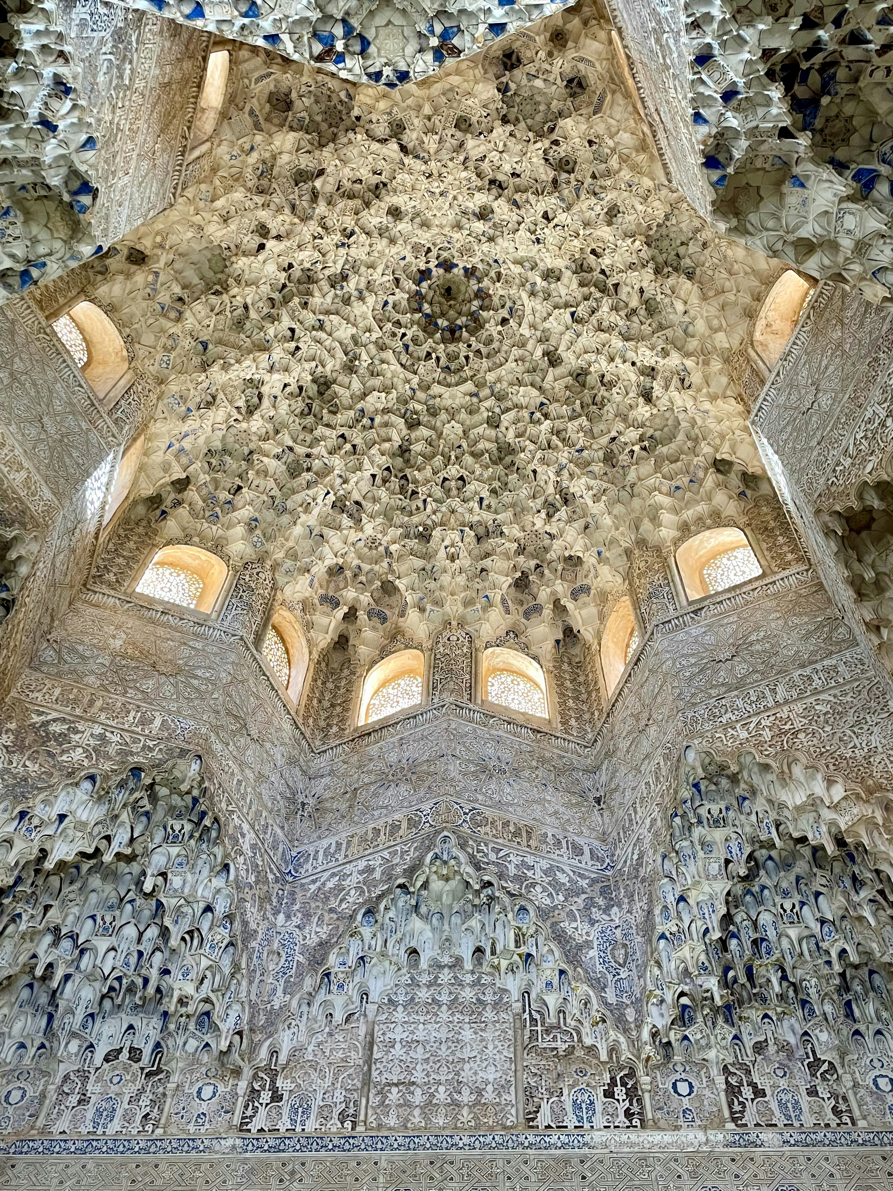 Intricate ceiling design in the Alhambra, showcasing a blend of geometric patterns and natural light filtering through ornate windows.