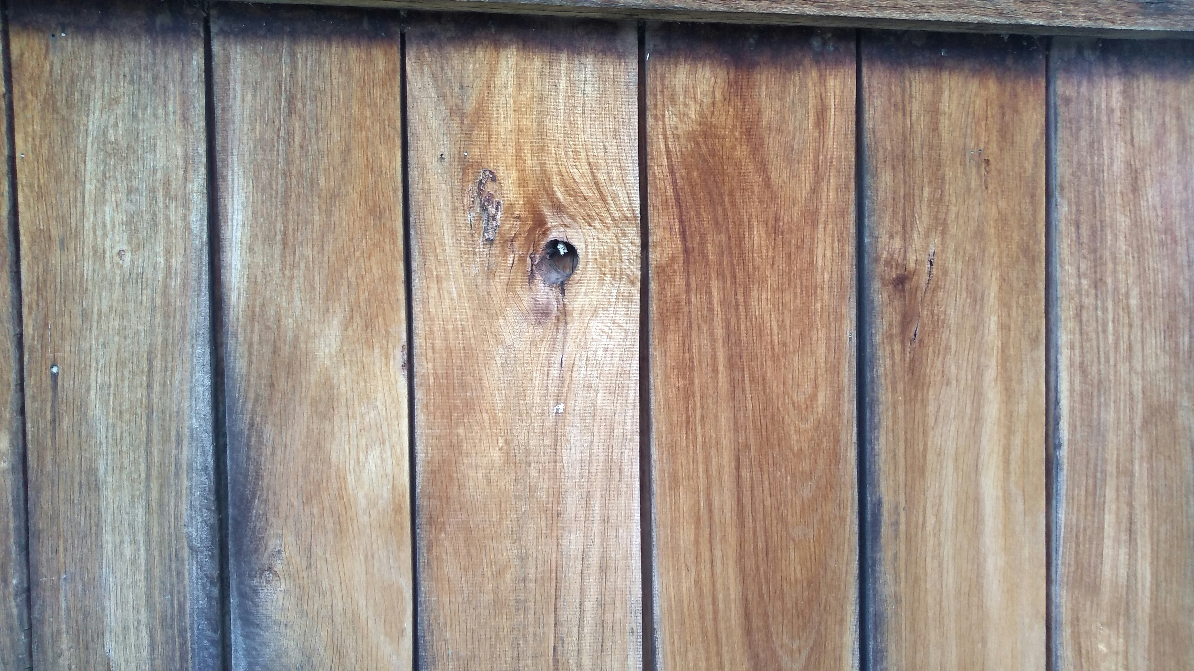 Close-up of weathered wooden planks showcasing natural textures and grain patterns. A distinct knot adds character to the rustic surface.