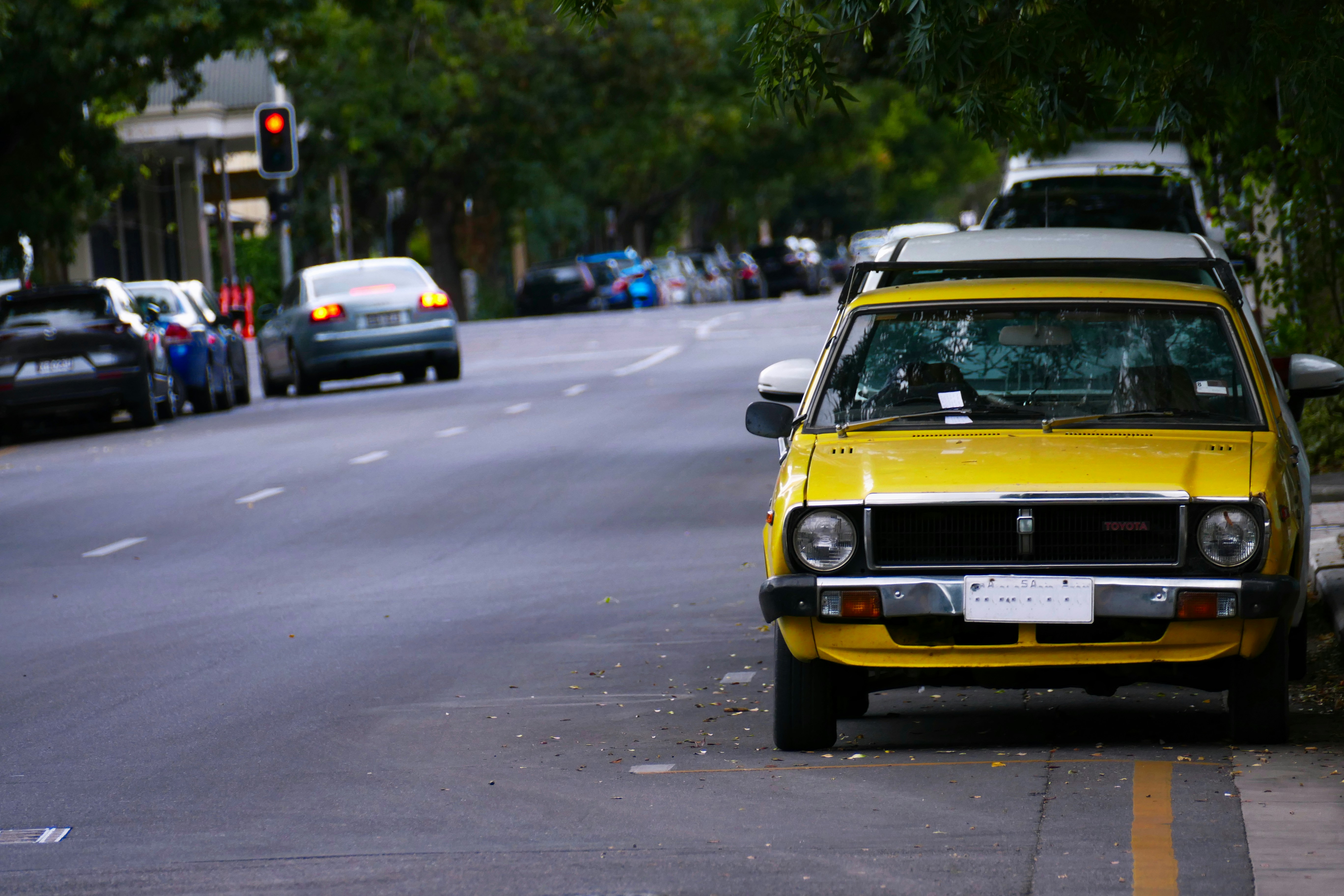 A yellow car parked on the side of the road photo – Free City Image on ...