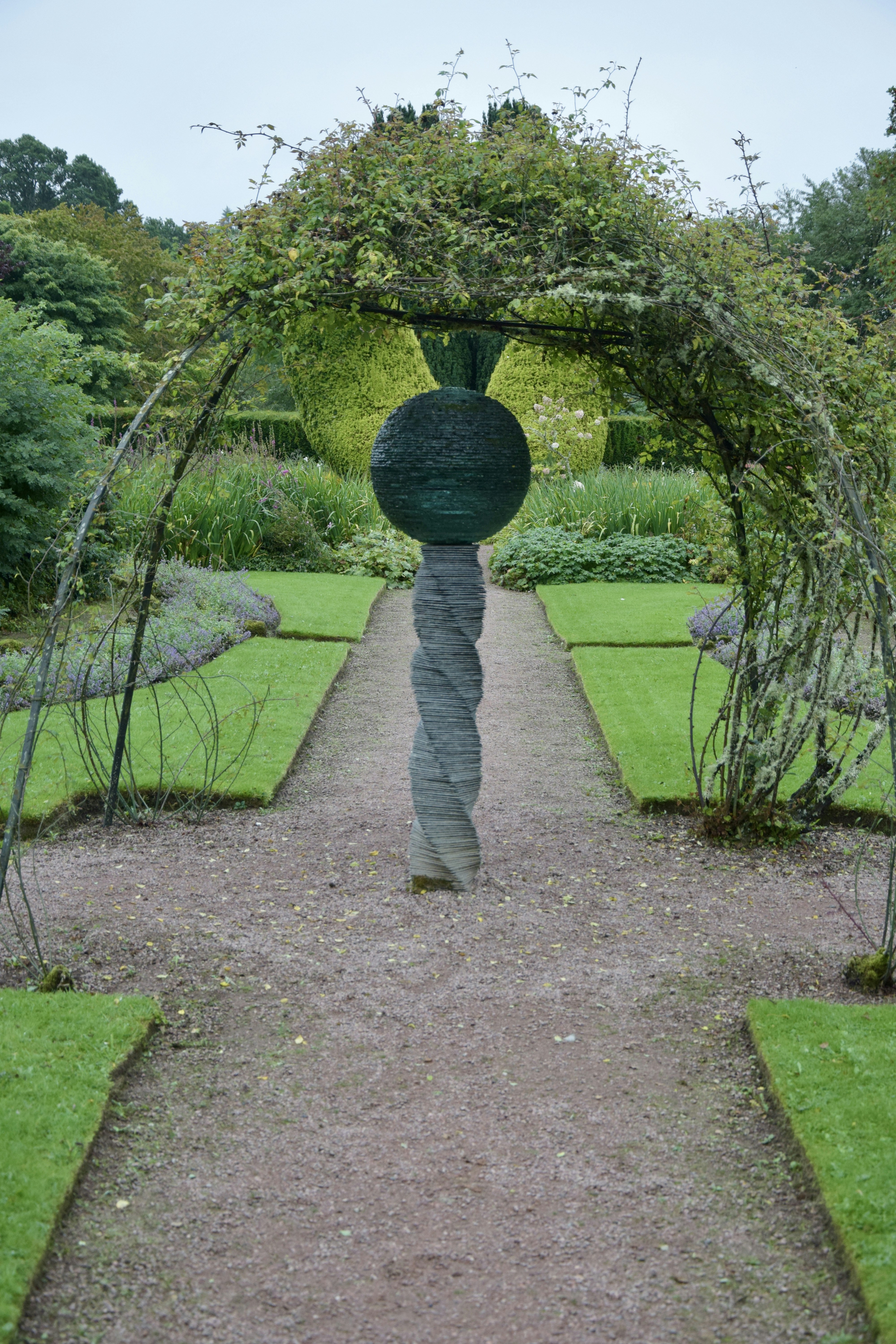 a garden with a path and a sculpture in the middle of it