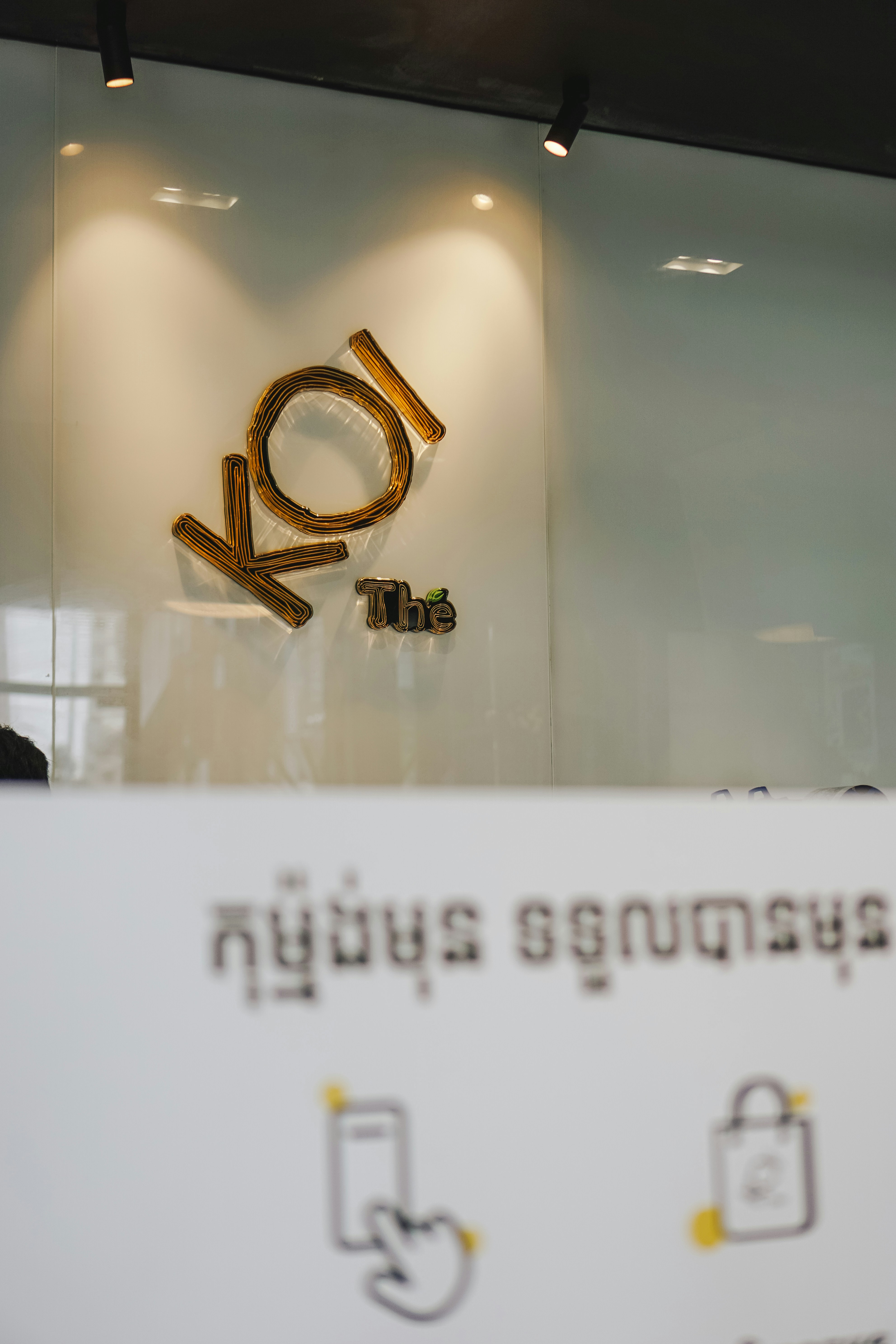 Wooden KO Logo Illuminates Glass Wall in Quiet Interior Lighting