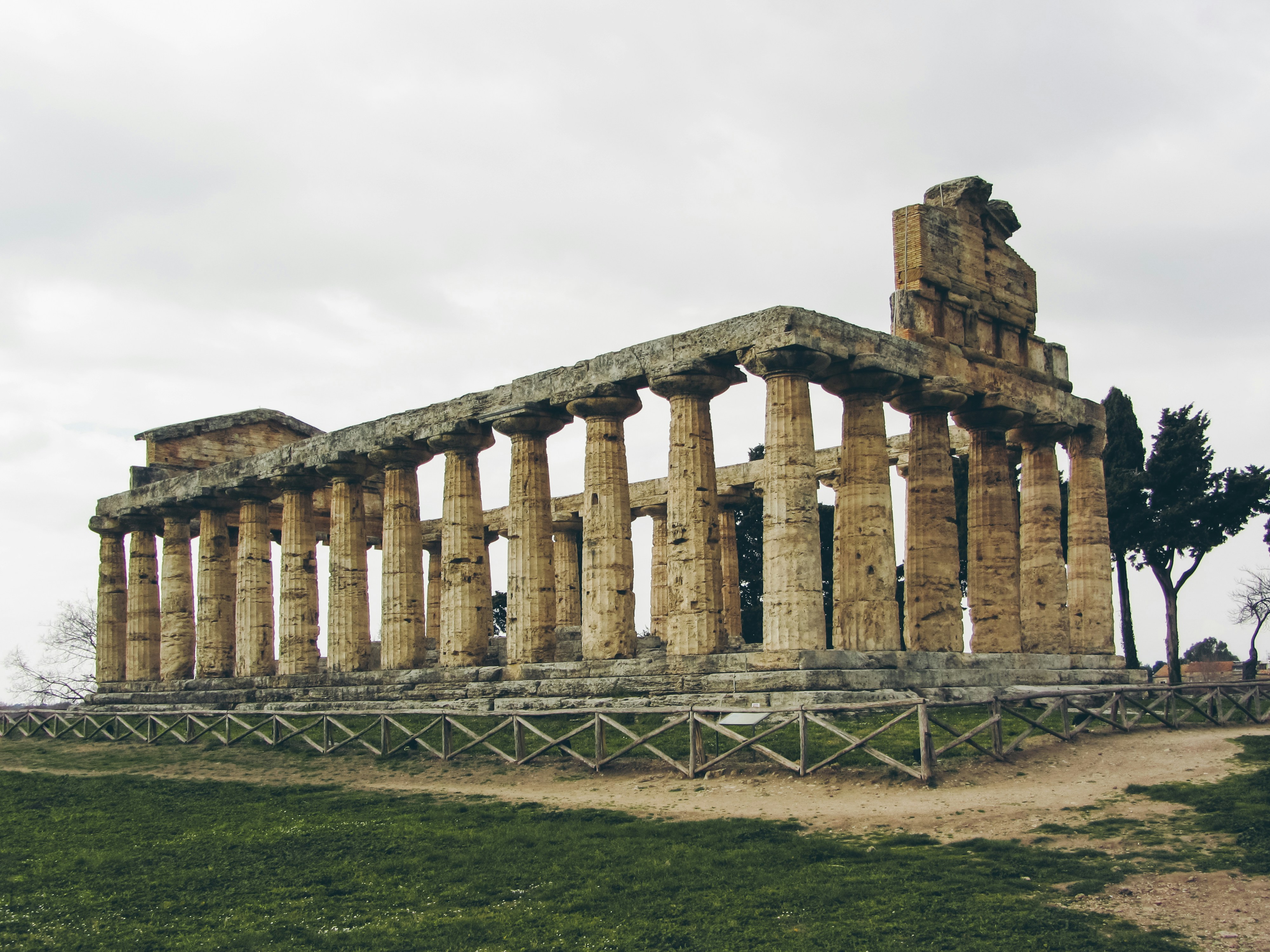 Temple of Athena (also known as the Temple of Ceres) in the Archaeological Site of Paestum, built around 500 B.C. | a large stone structure sitting on top of a lush green field