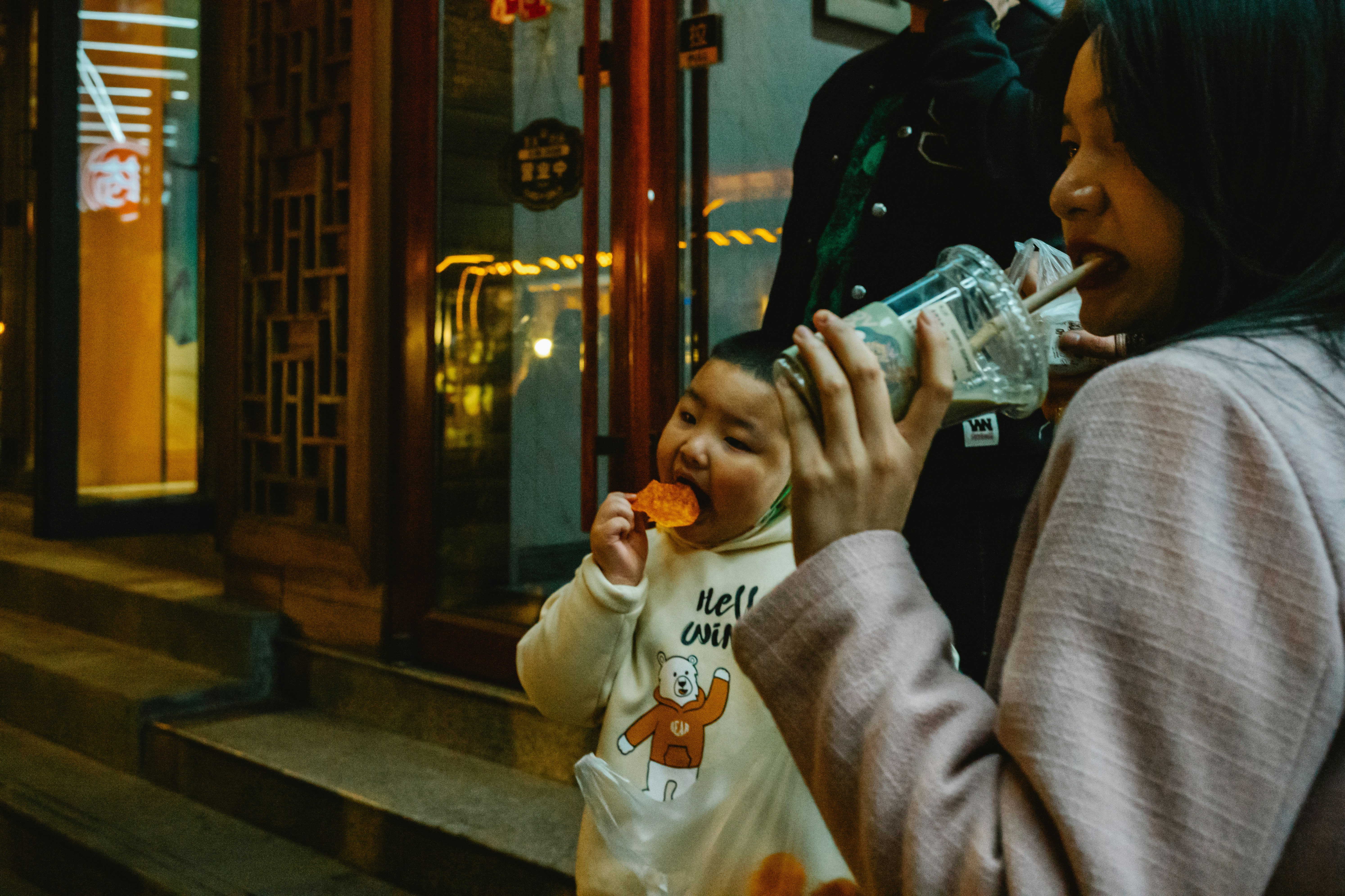 A woman and a child eating food outside of a building photo – Free ...