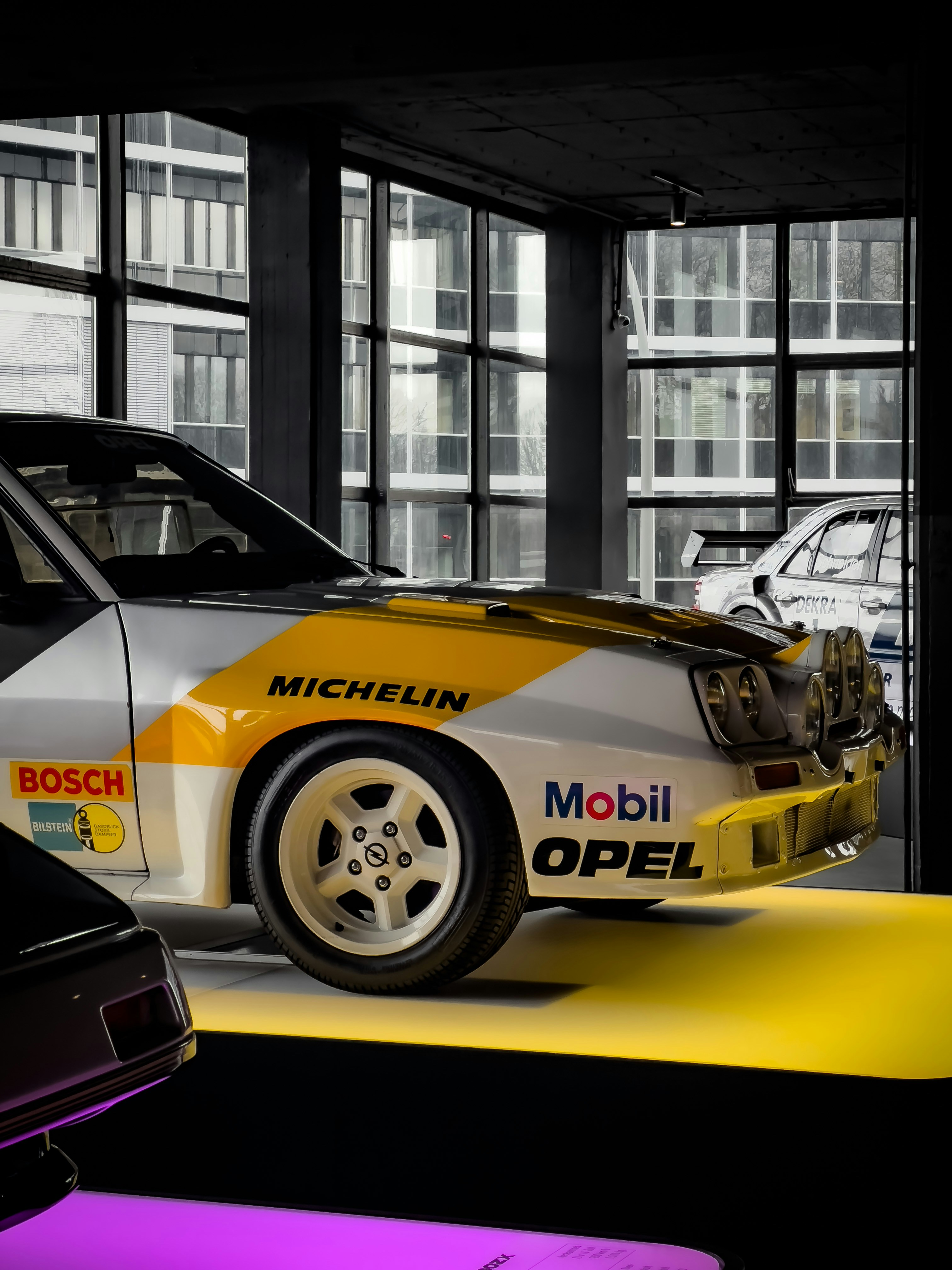 Livery and Light: A Vintage Opel Rally Car in a Glass-Walled Showroom