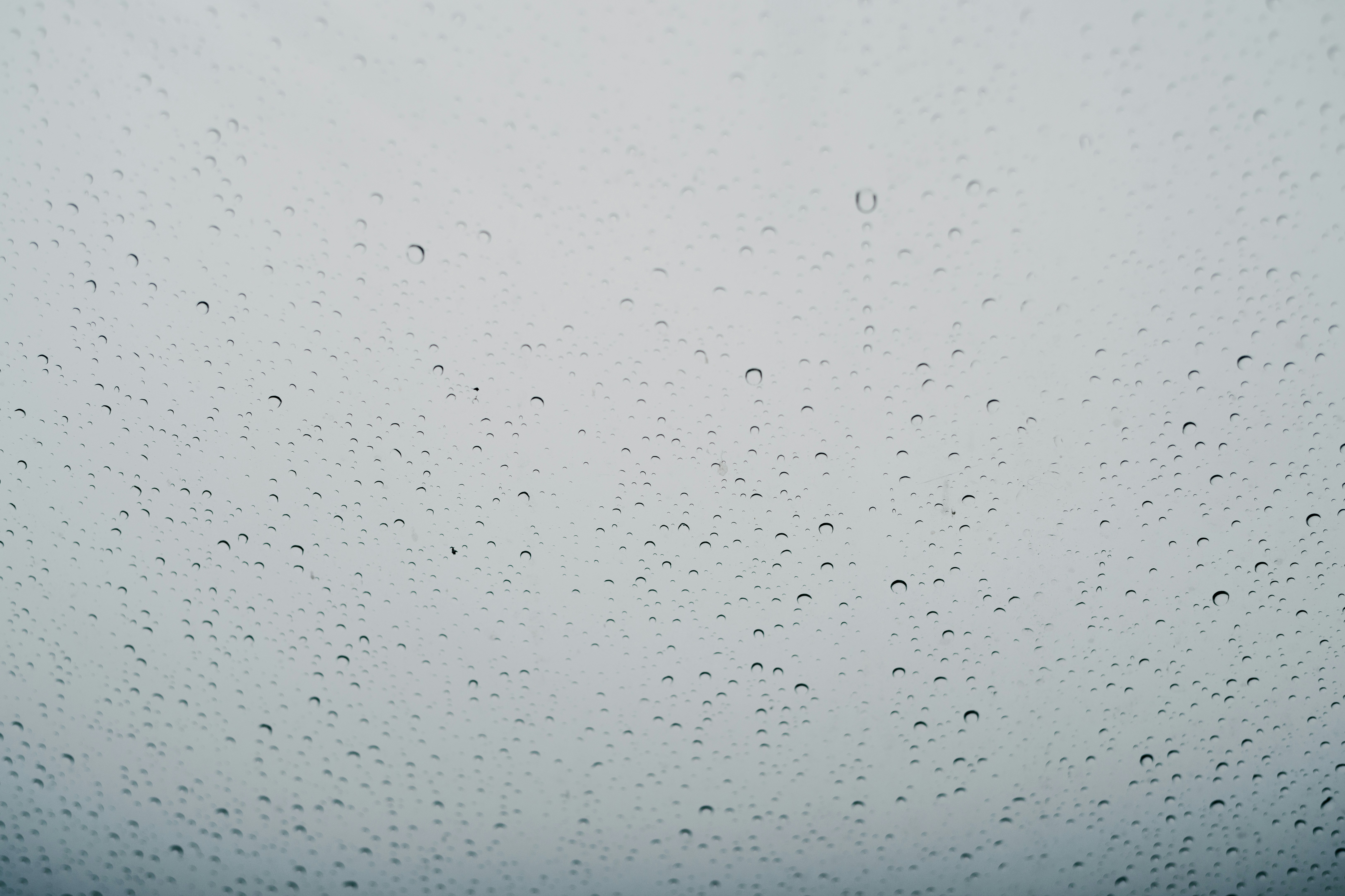 Raindrops scattered across a glass surface under a gray sky.