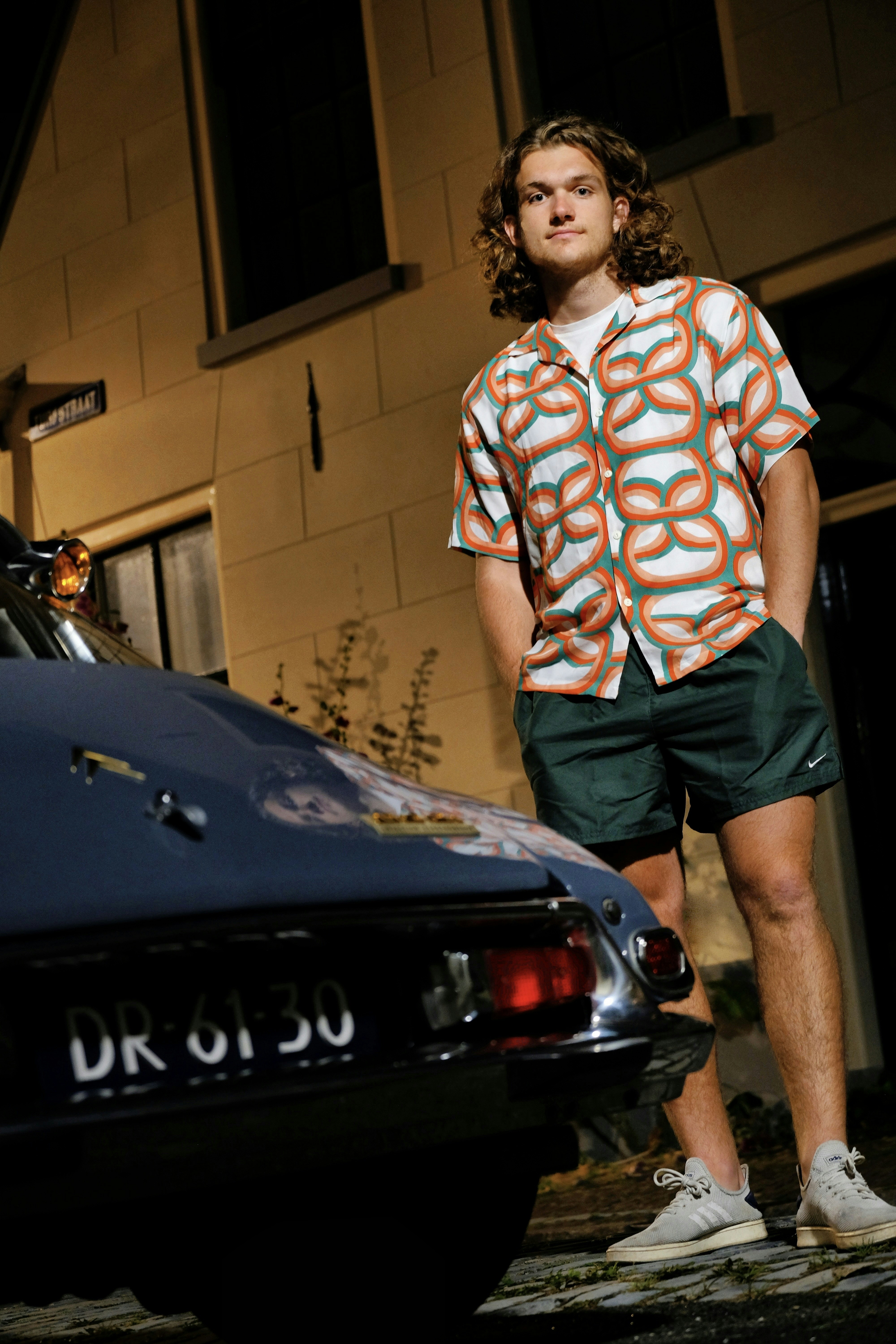 Neon-patterned breeze: a relaxed pose beside a vintage car