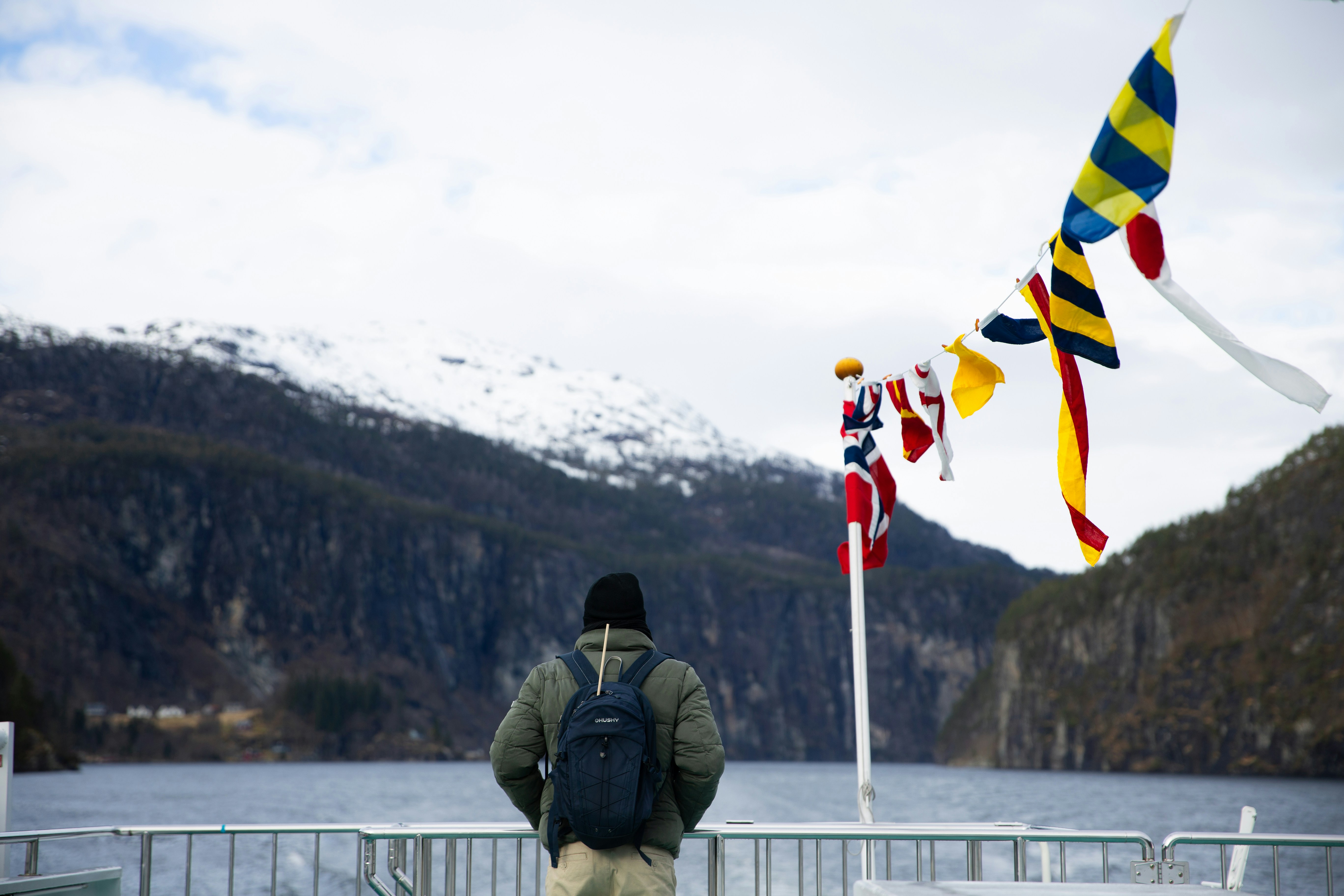 Backpacker at the Fjord: Colorful Flags Framing a Quiet Horizon