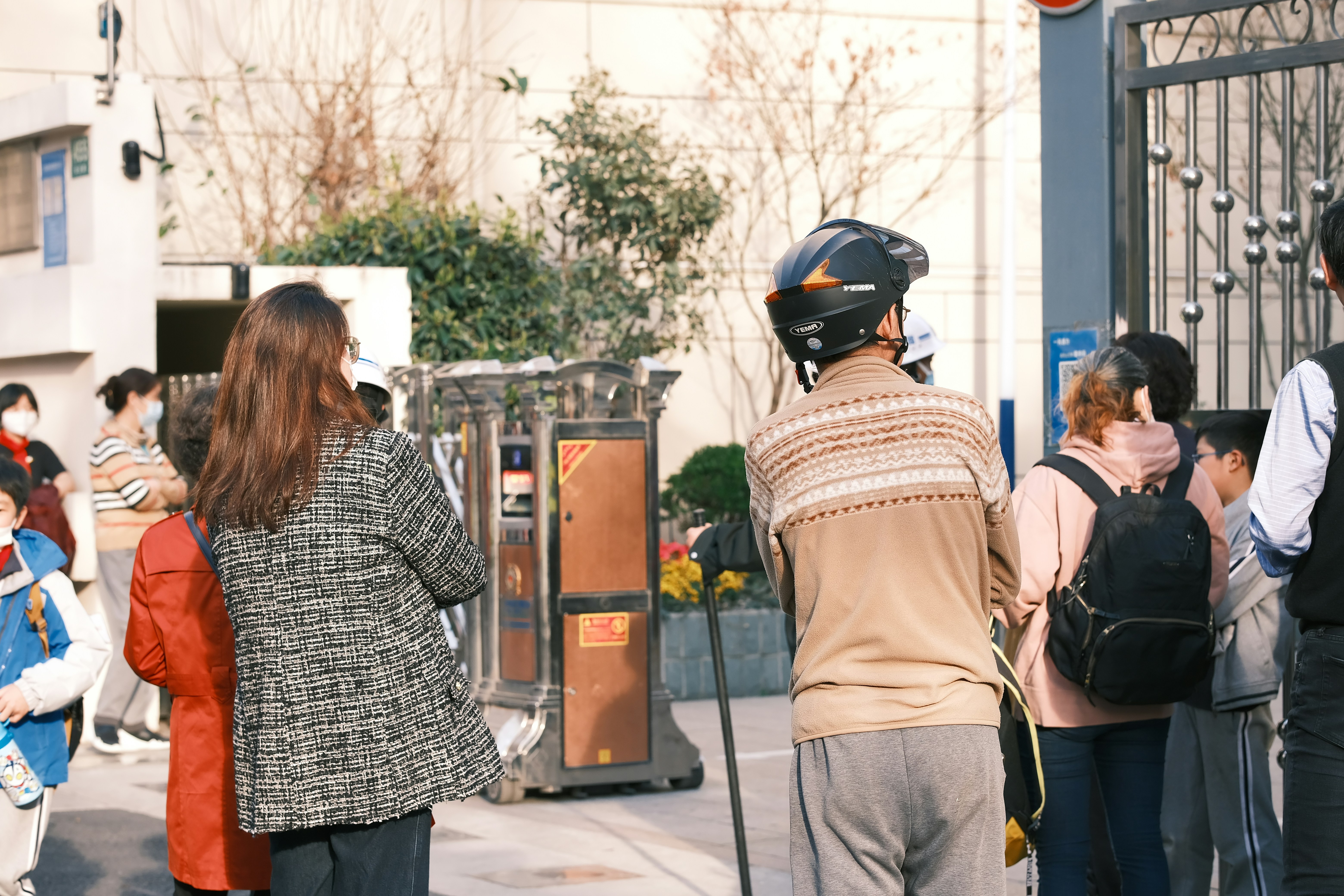 Helmeted Pause in a City Queue