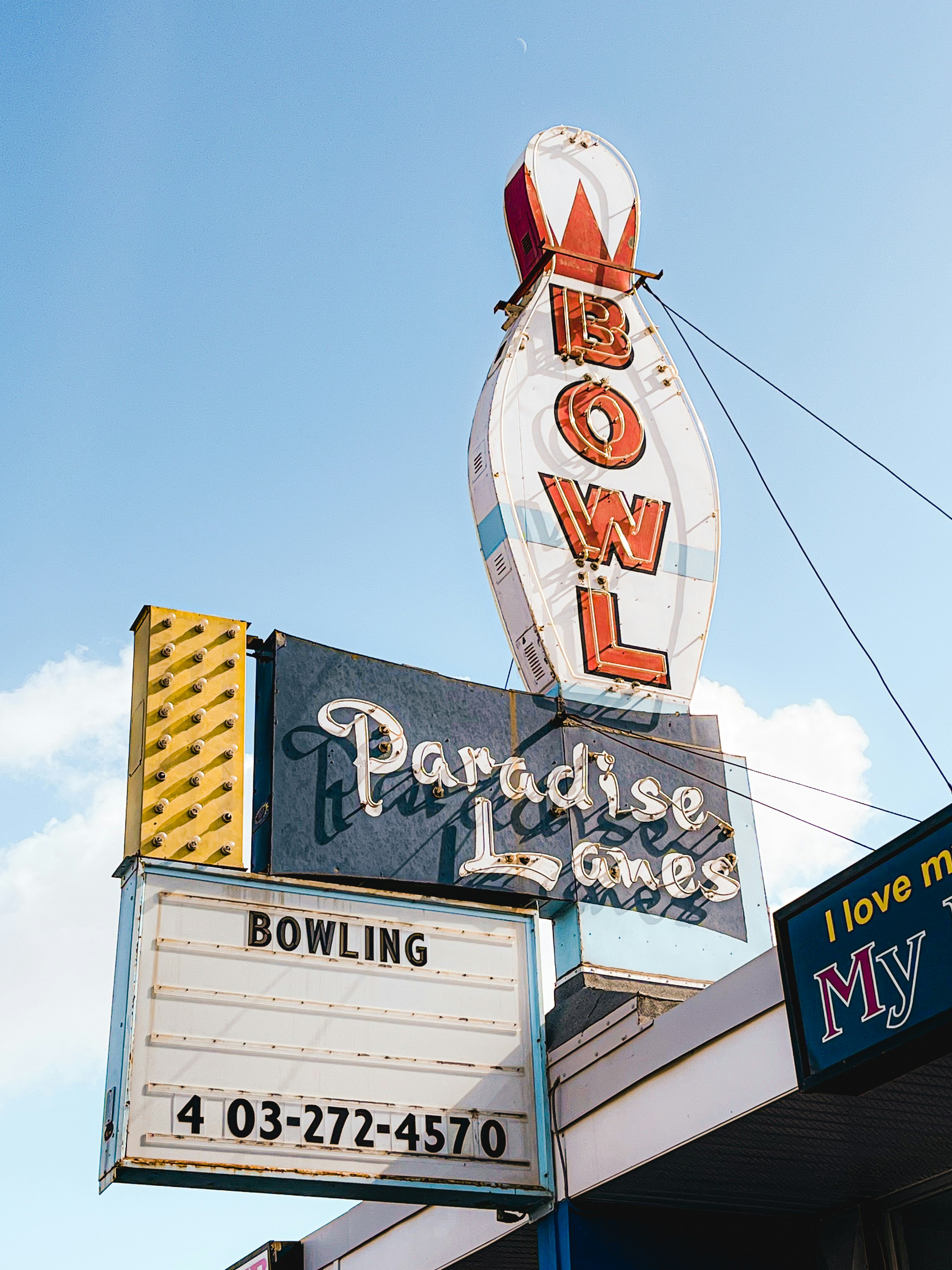 Vintage bowling alley sign featuring a large bowling pin and retro lettering against a bright sky. Perfectly captures the charm of classic entertainment venues.