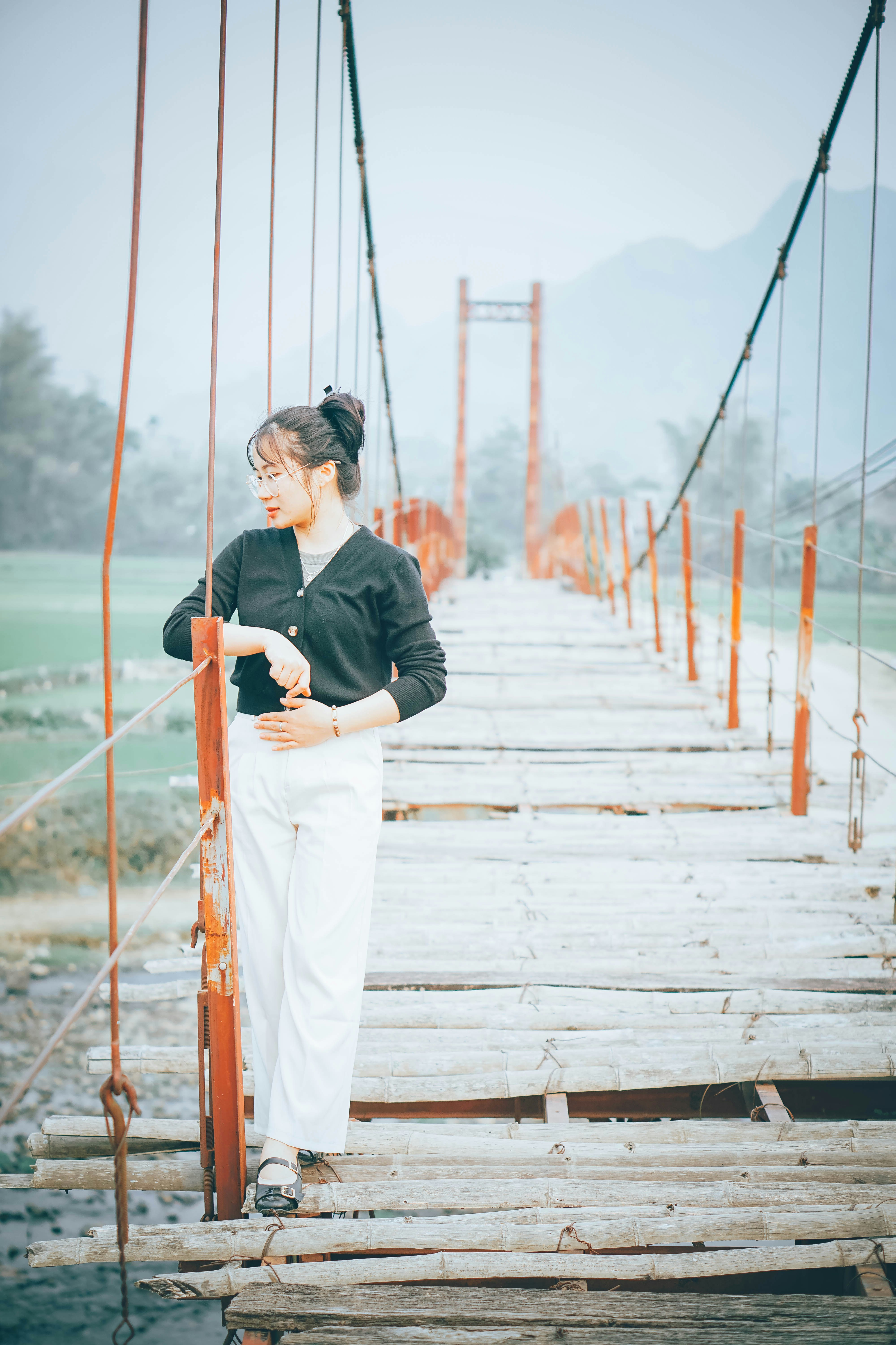 a woman standing on a bridge with her hands on her hips
