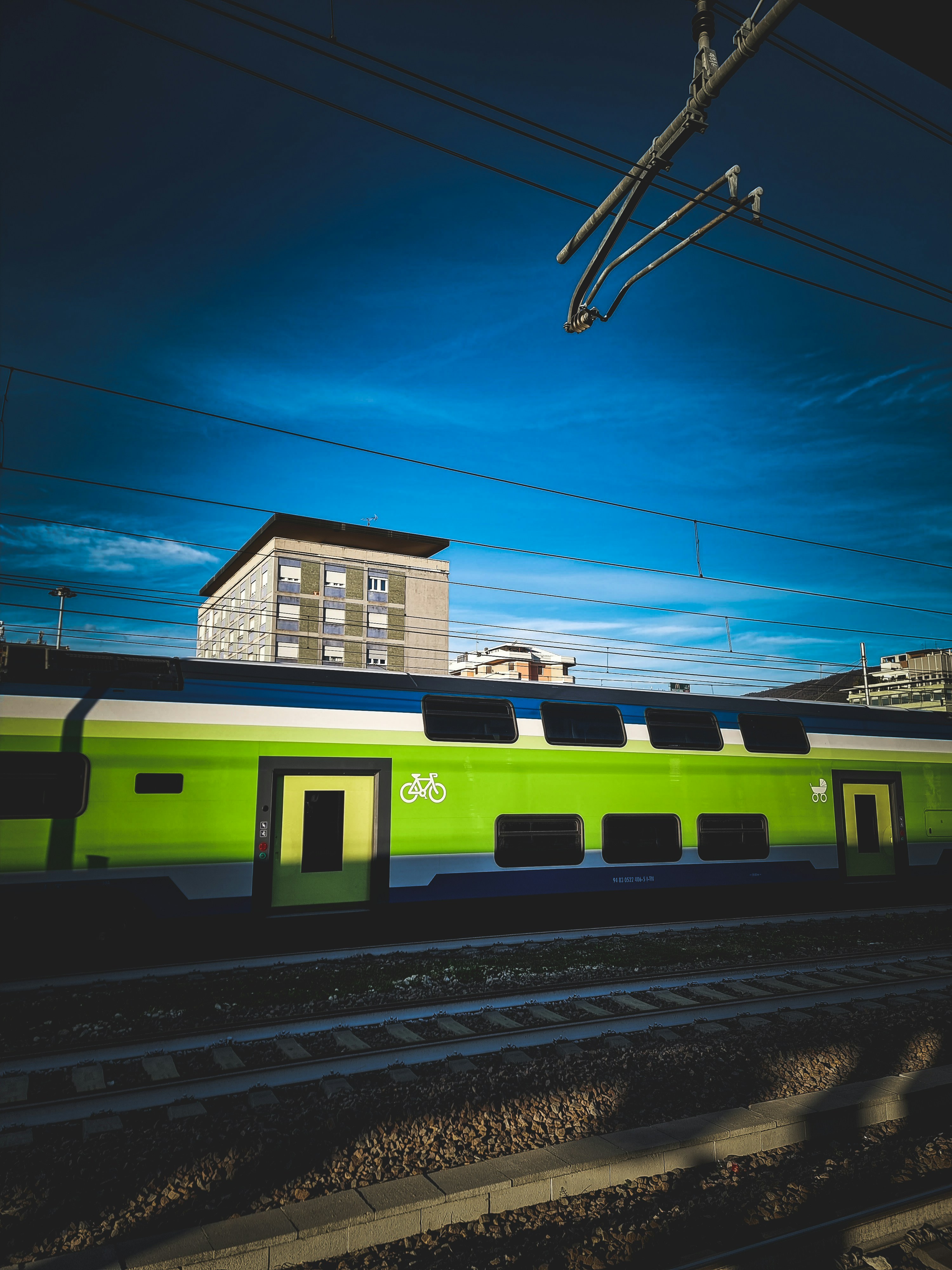A green train traveling down train tracks next to a tall building photo ...