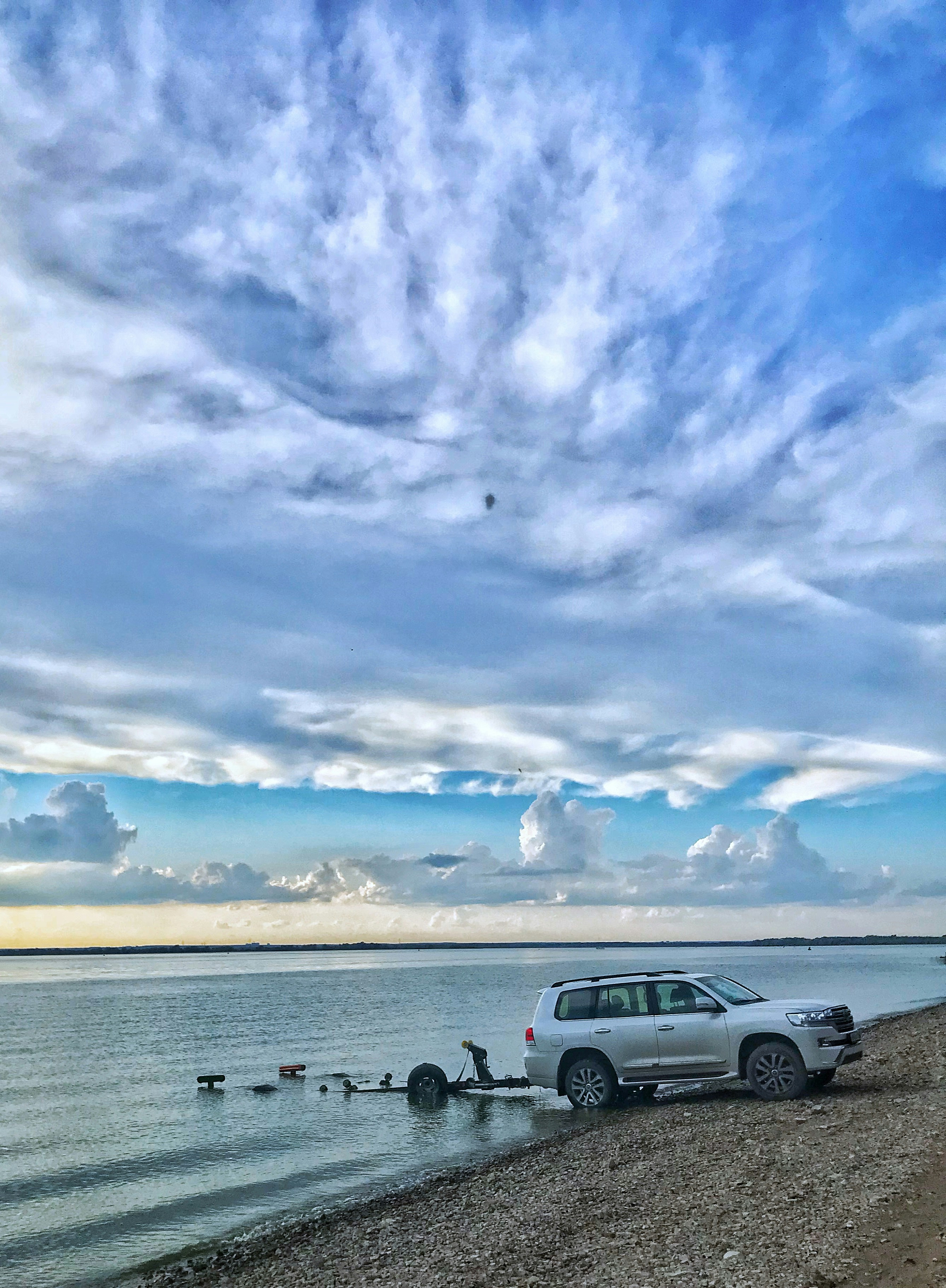 Shoreline Rendezvous: A White SUV at the Edge of a Calm Coastal Beach