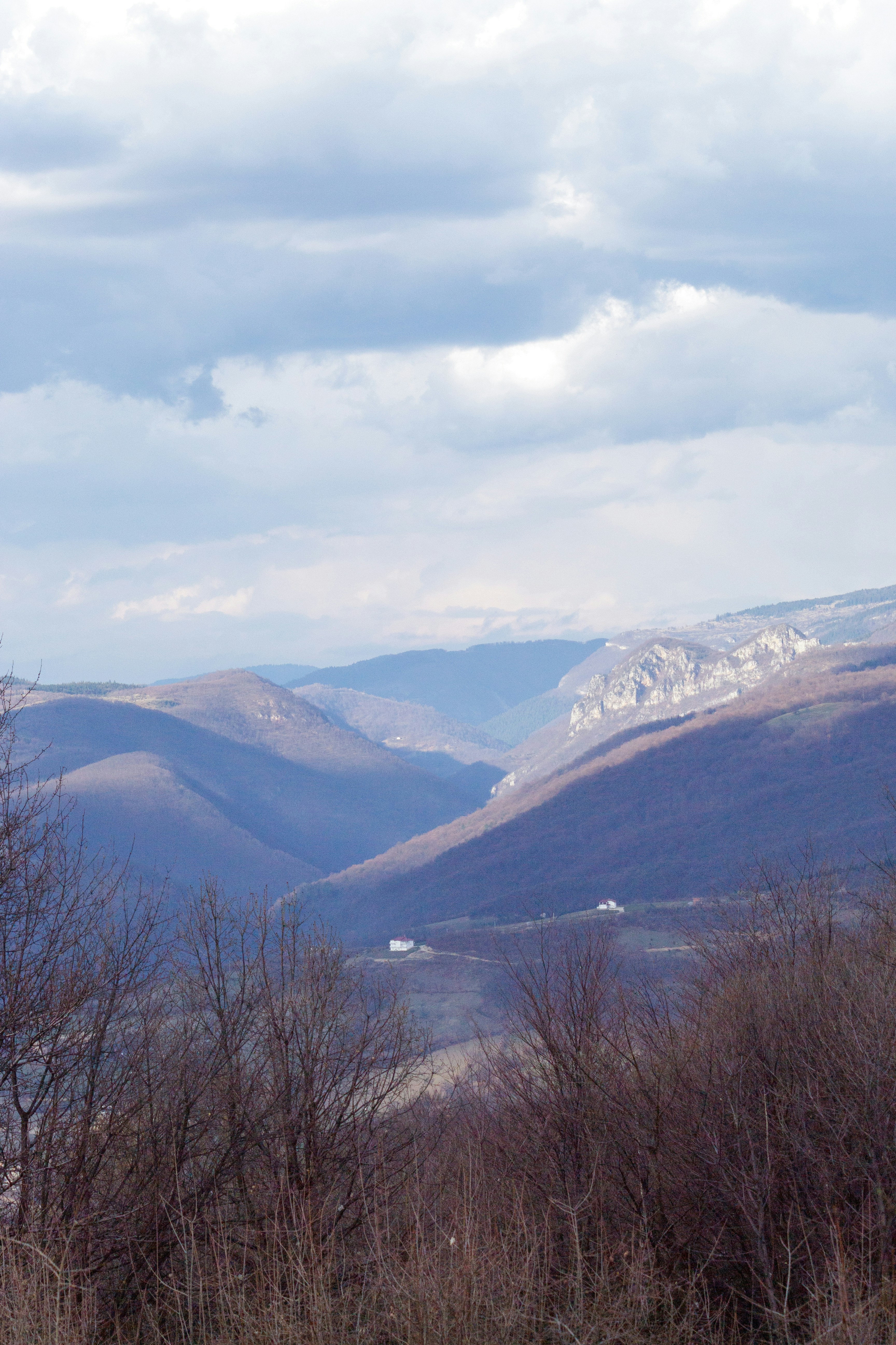 Lone White House Amid Valley Ridges Beneath Layered Clouds