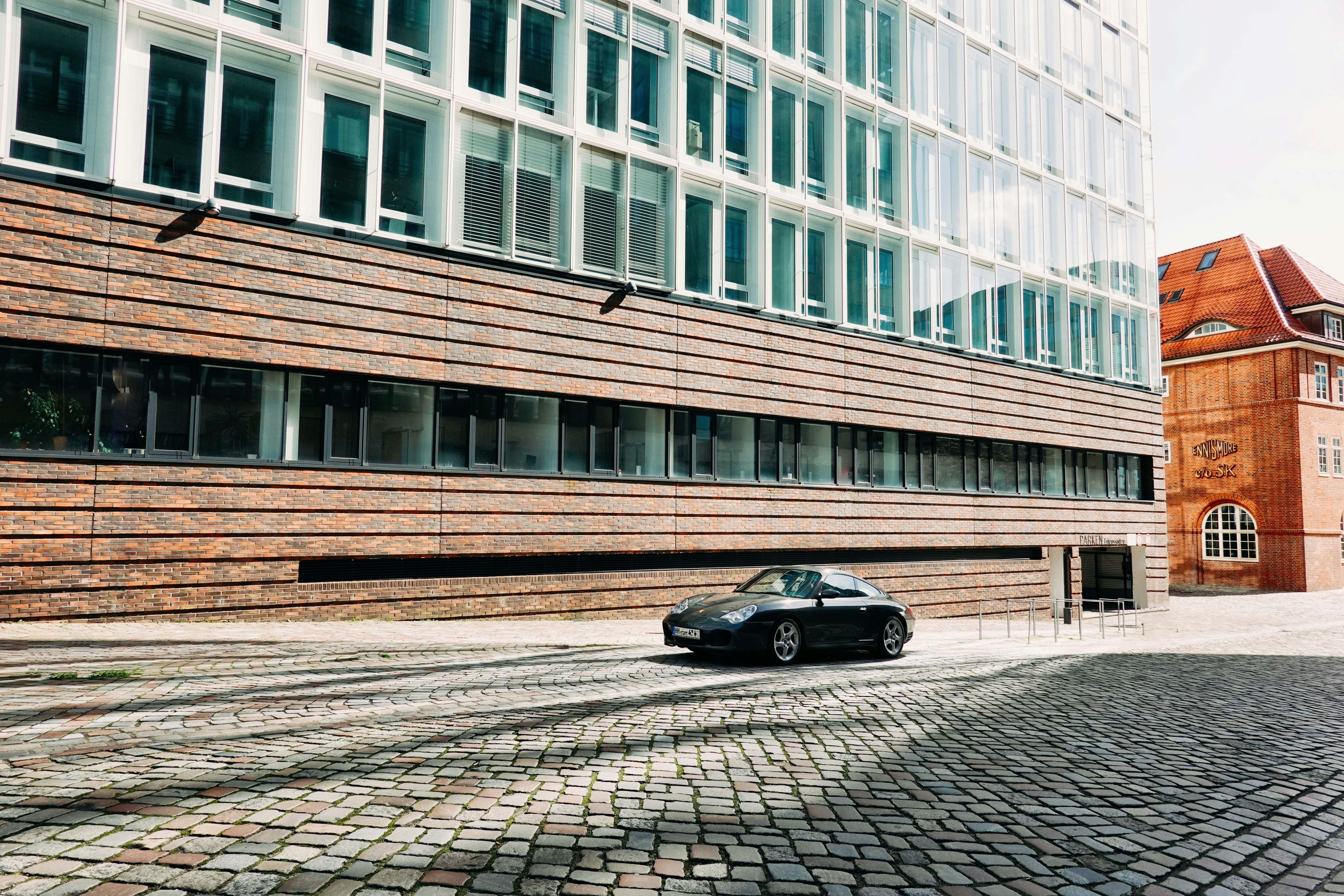 Cobblestone Calm: Black Convertible Between Brick and Glass