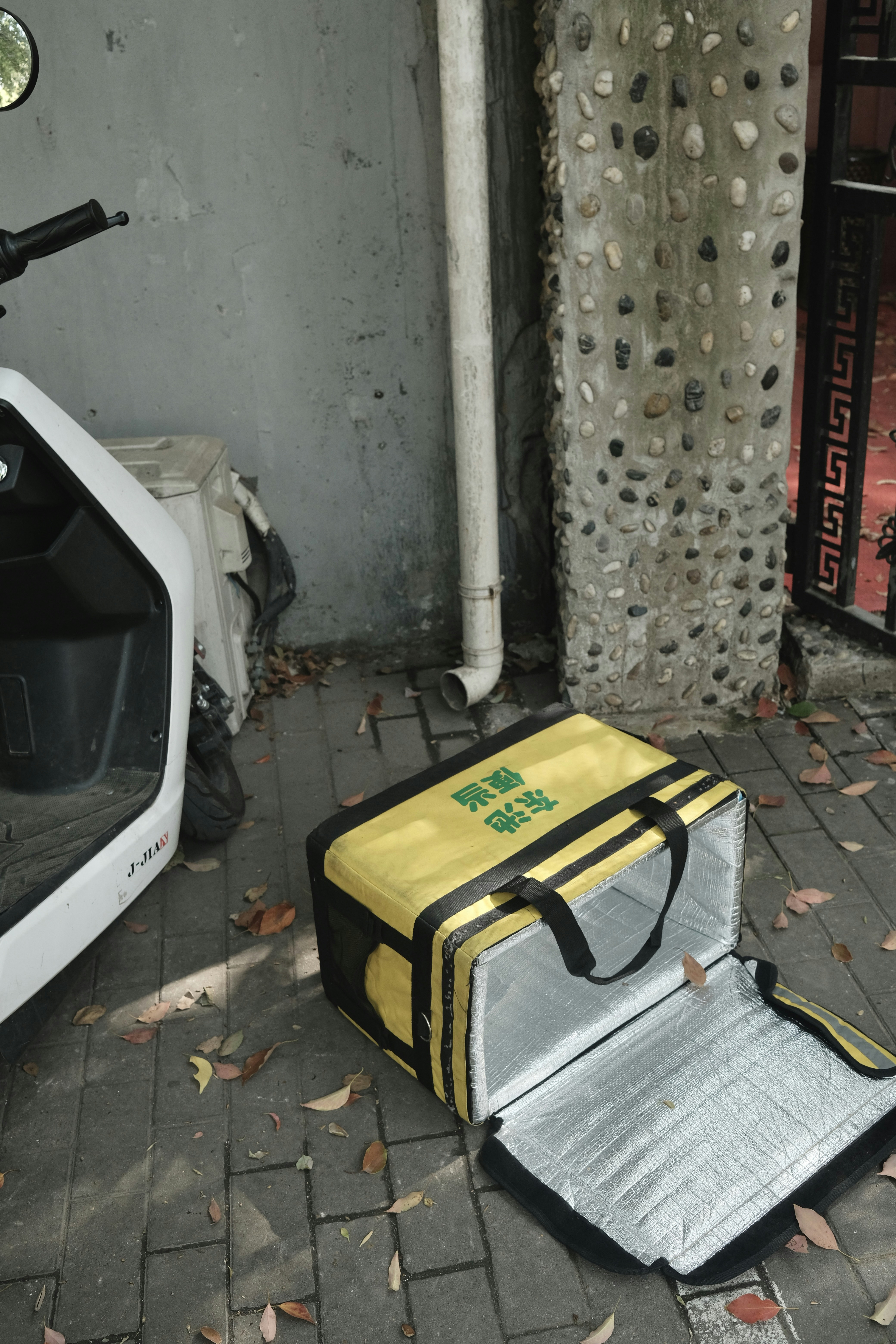 Threshold of Delivery: A Yellow Insulated Bag Resting by a White Scooter