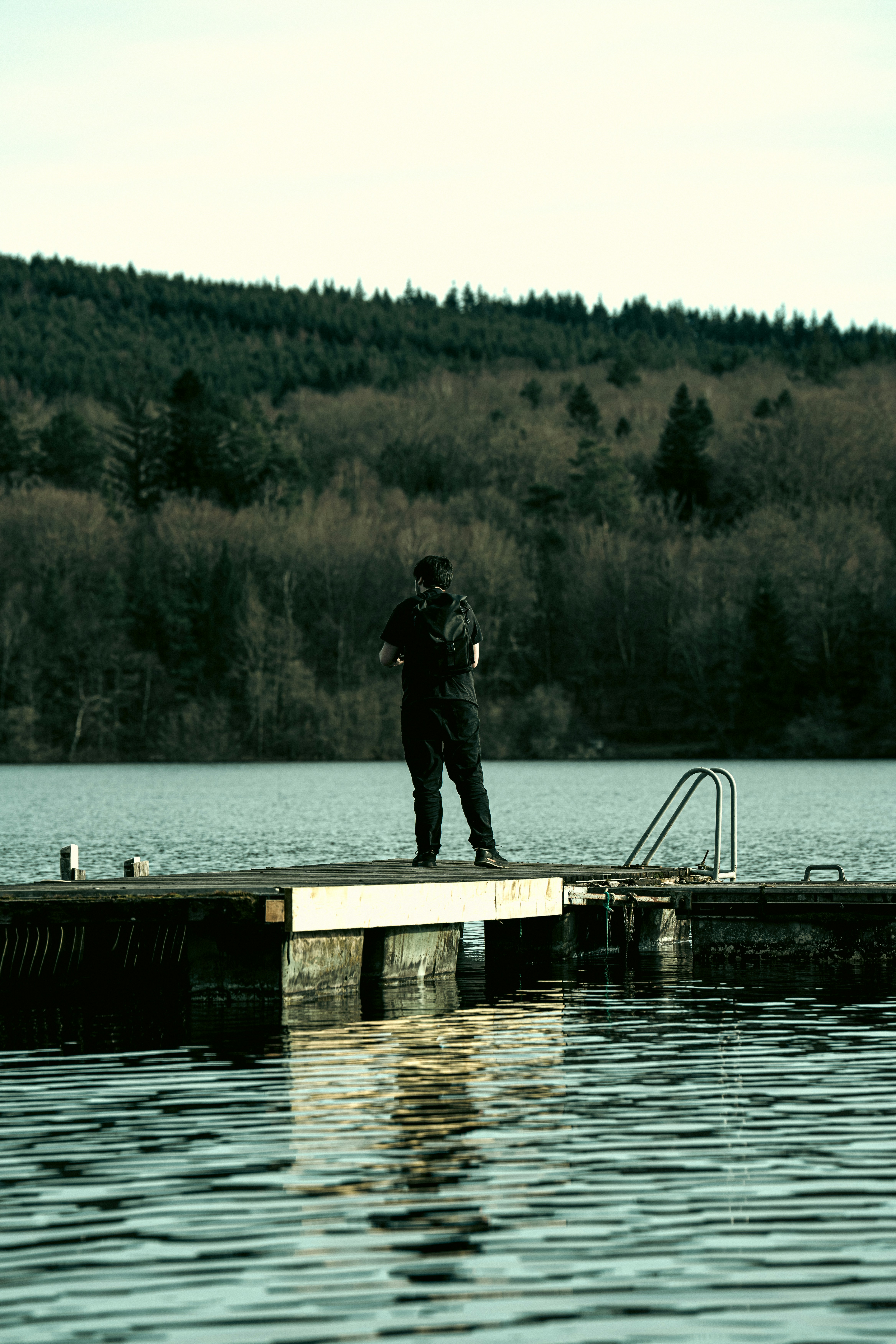 a man standing on a dock next to a body of water