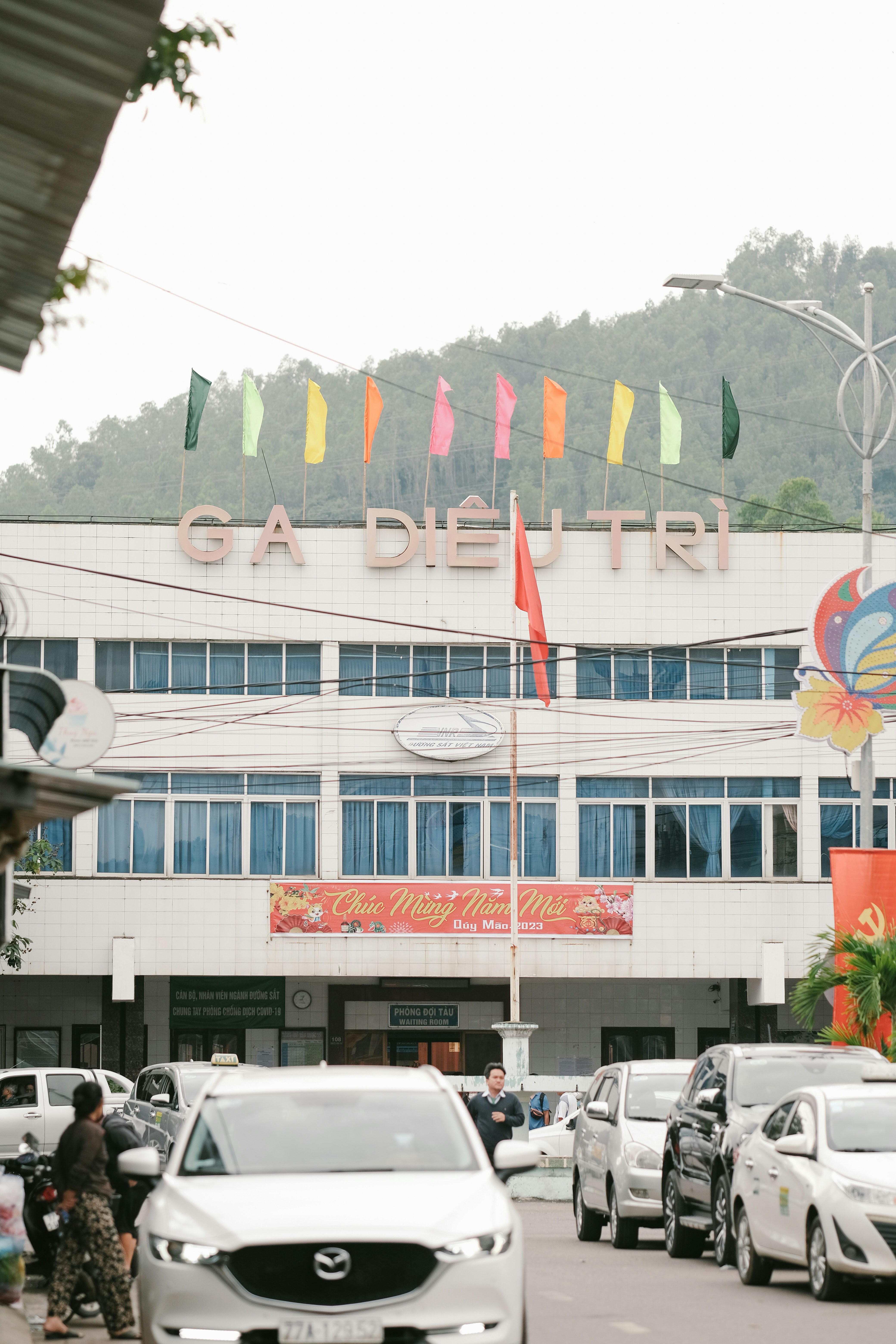 Flag-Crowned Facade Over Morning Traffic