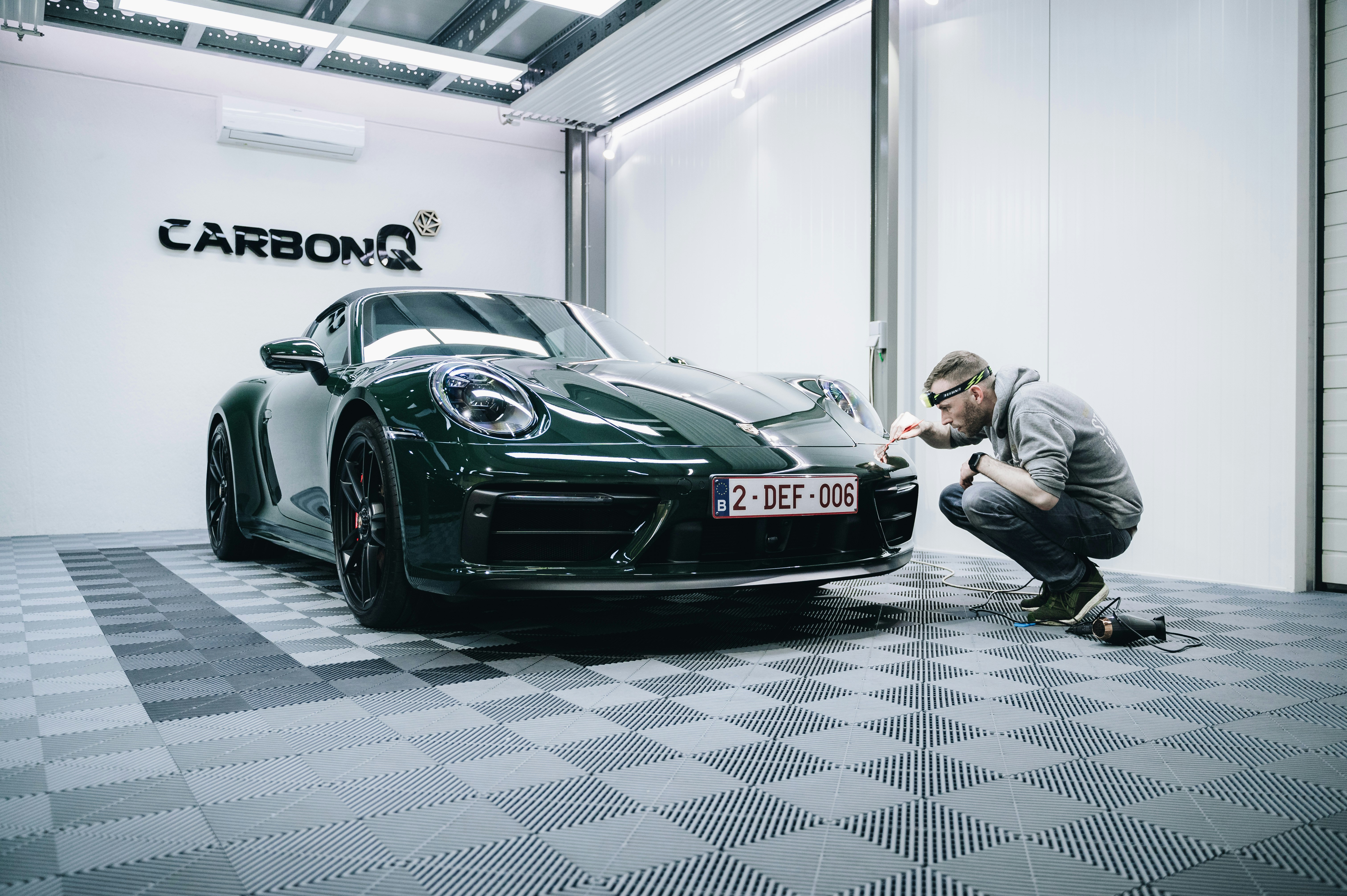 A meticulous car enthusiast inspects a sleek green sports car in a modern detailing studio, showcasing the intersection of craftsmanship and automotive beauty.