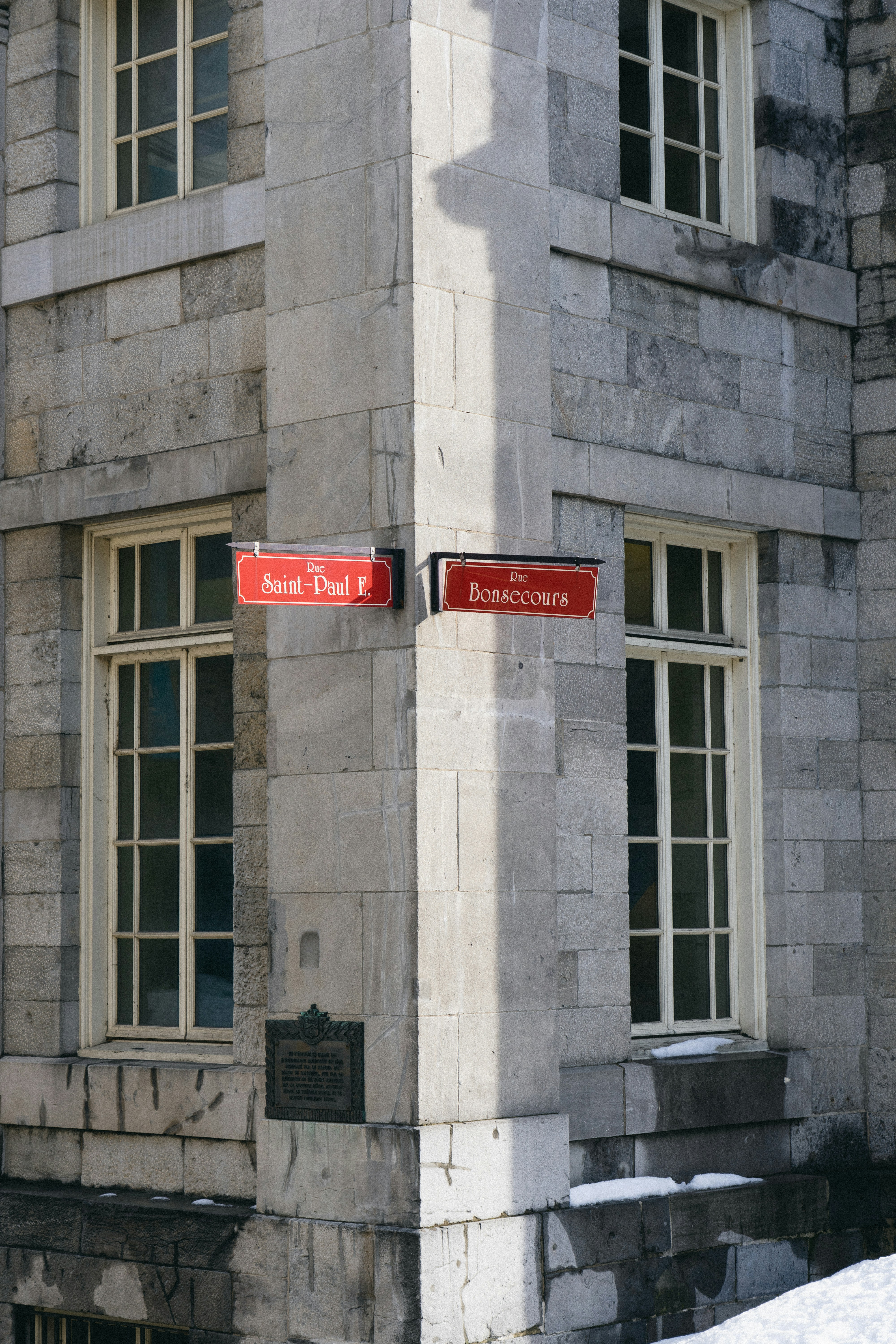 Red Street Signs at a Snow-Dusted Stone Corner (Saint-Paul & Bonsecours)