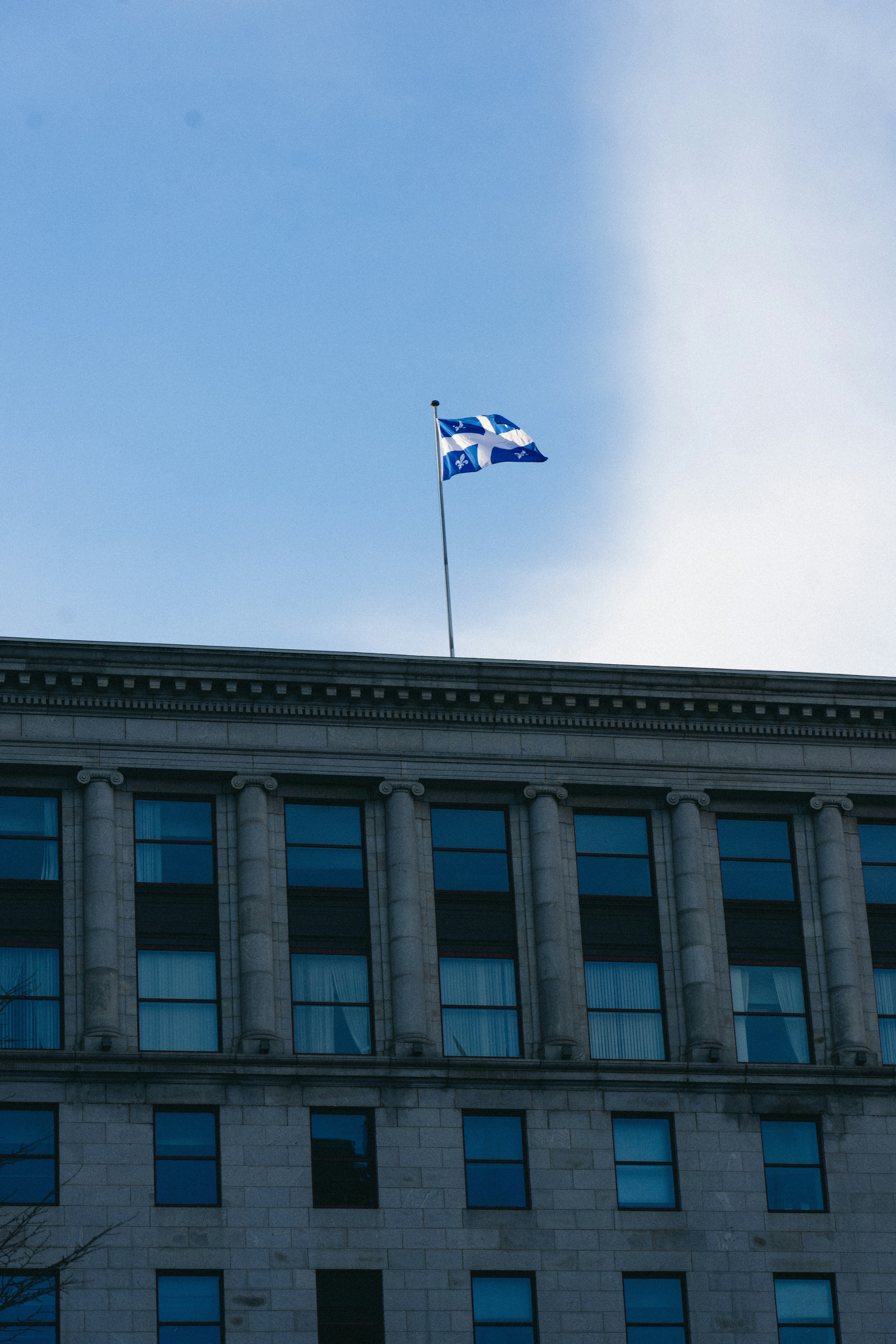 Flag atop a classic stone facade under a clear blue sky