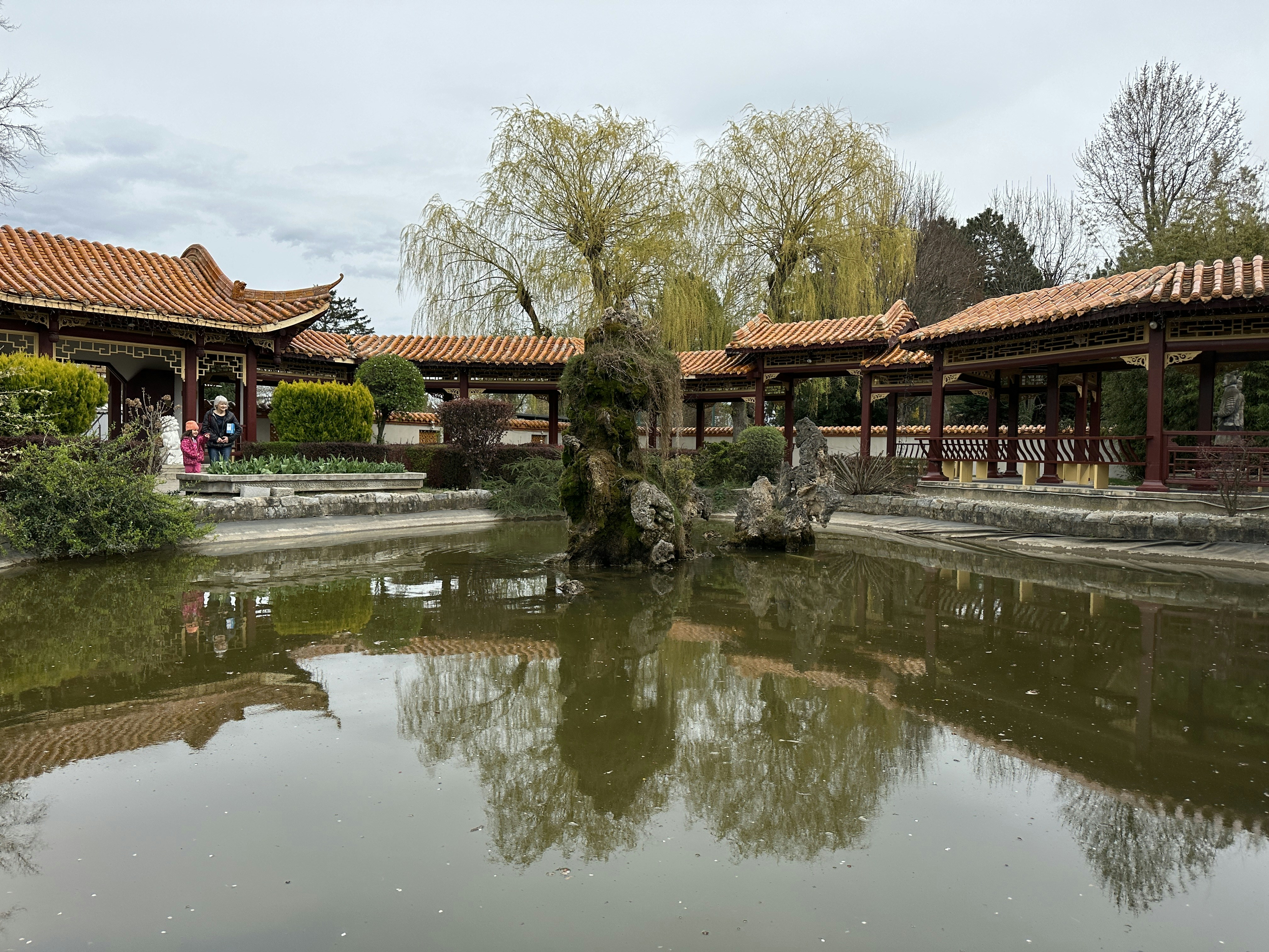 a pond in a park with a building in the background