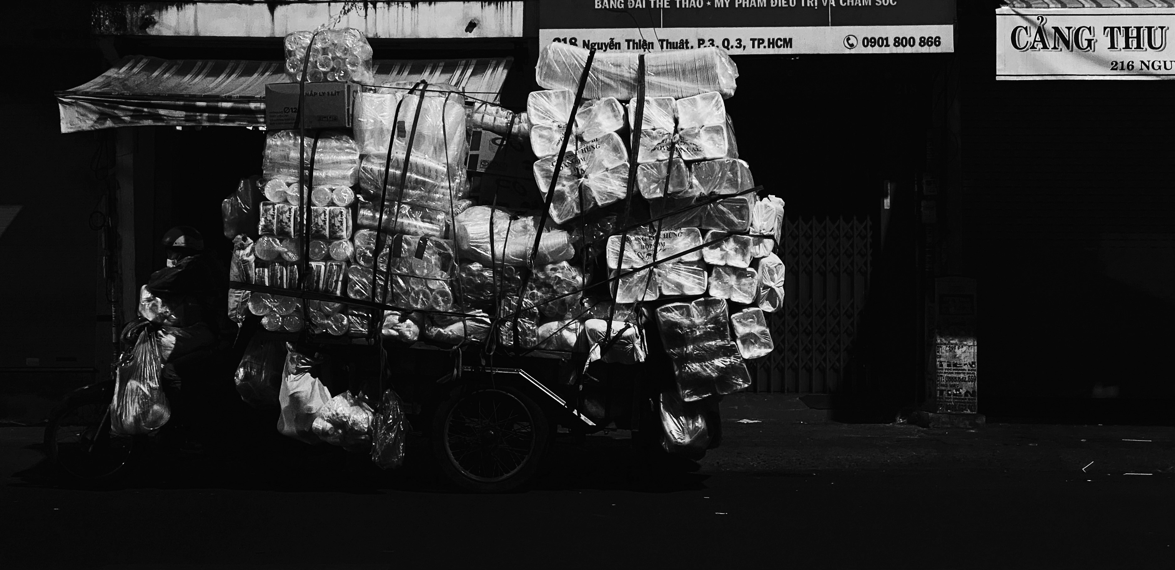 Monochrome Load: A Street Cart Burdened with Wrapped Goods