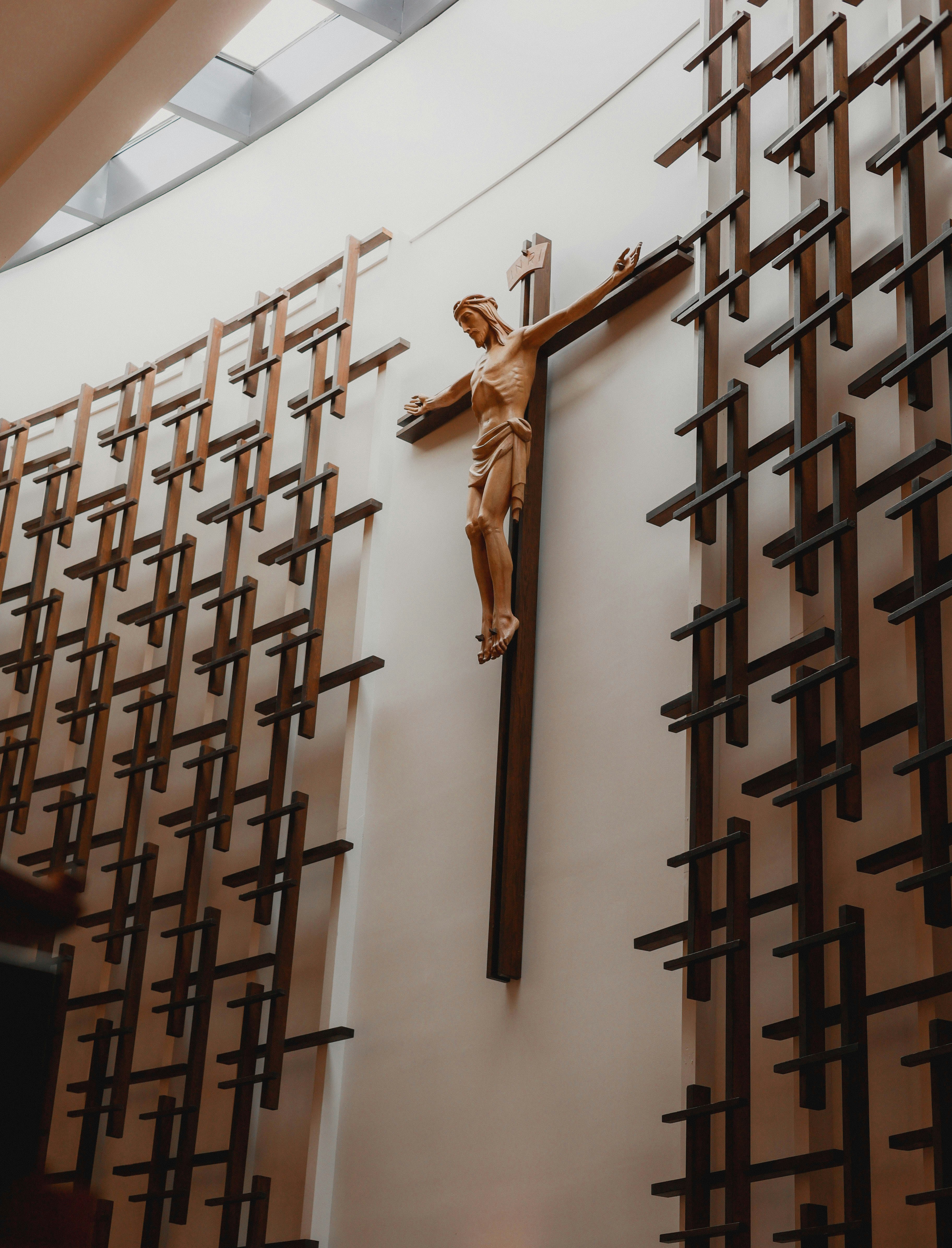 Wooden crucifix mounted on a minimalist wall, surrounded by geometric wooden patterns, evoking a sense of serenity and reflection.