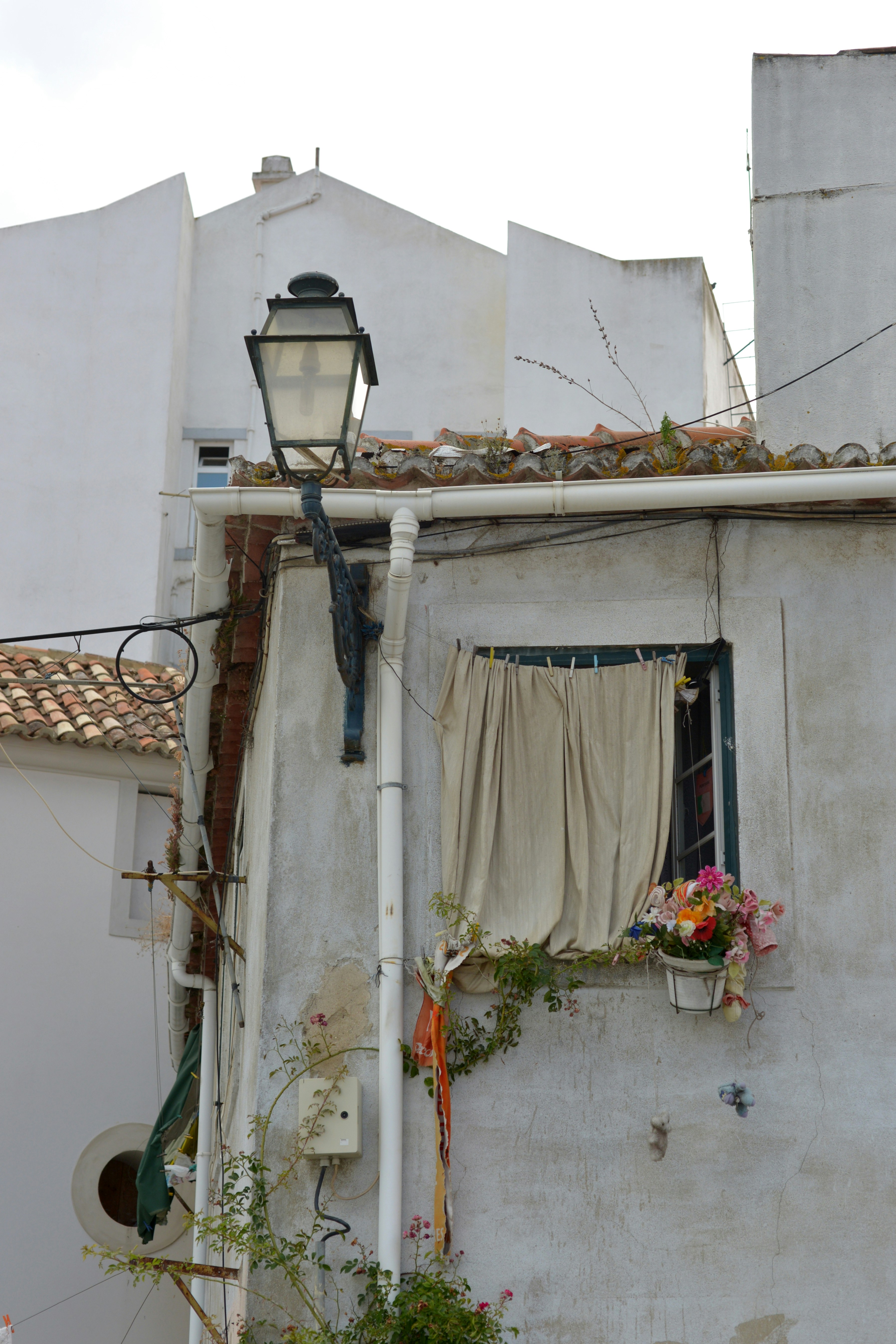 Facade with Laundry and Flower Basket under an Old Street Lamp