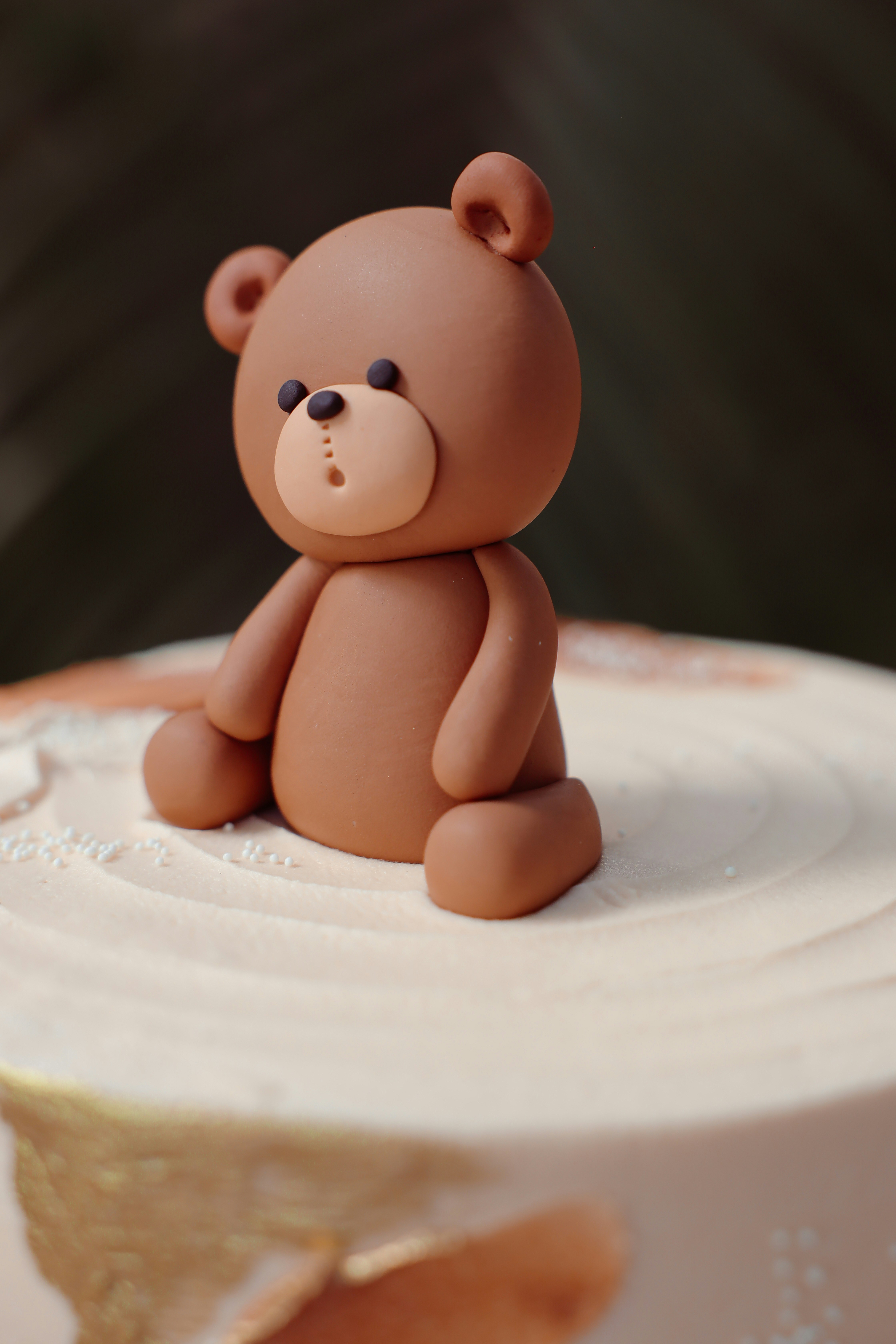 Tiny Clay Bear Stands Guard on a Cream-Cake Summit