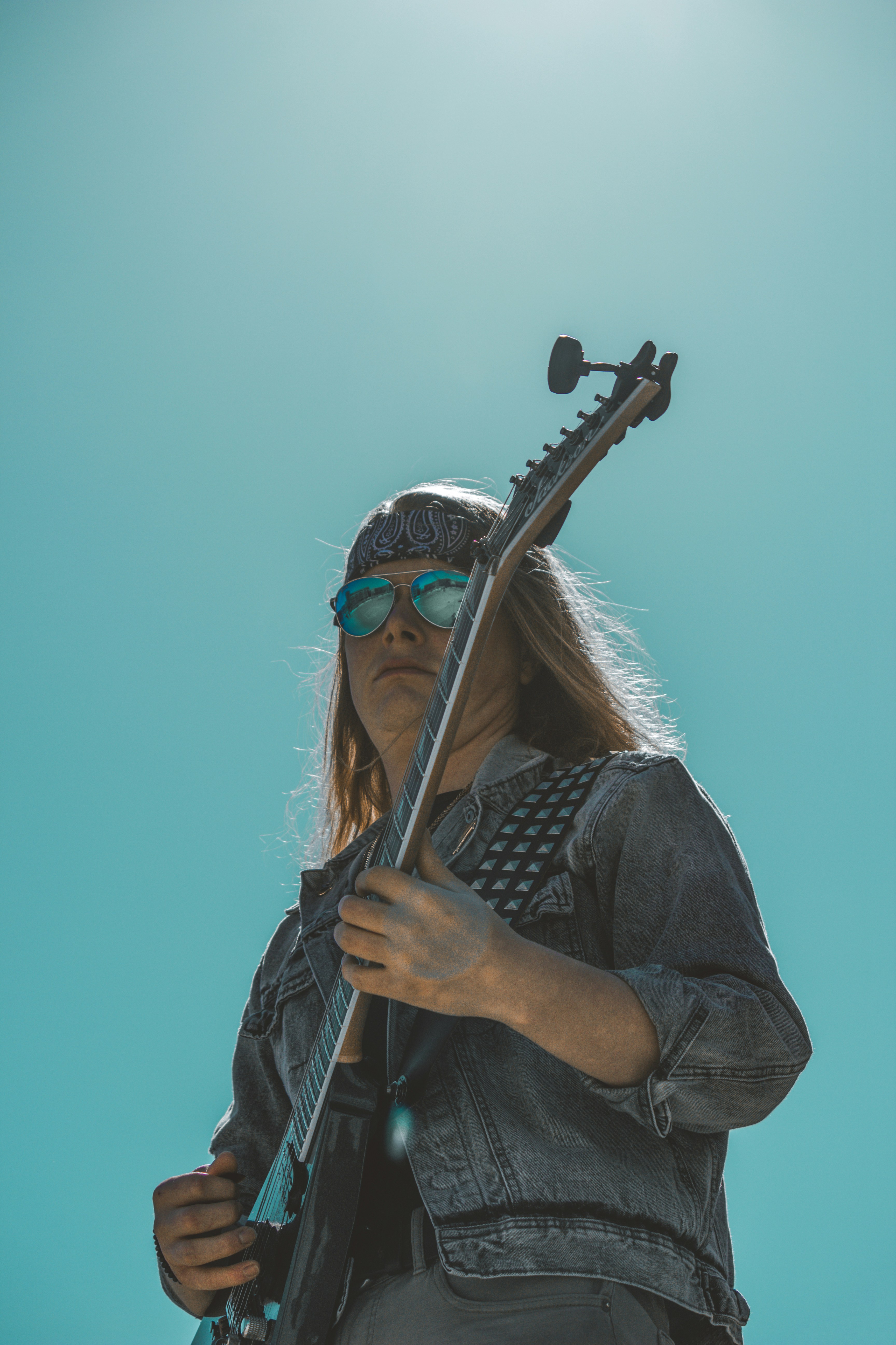 Turquoise Sky Riff: A Denim-Guitar Portrait in Bright Daylight